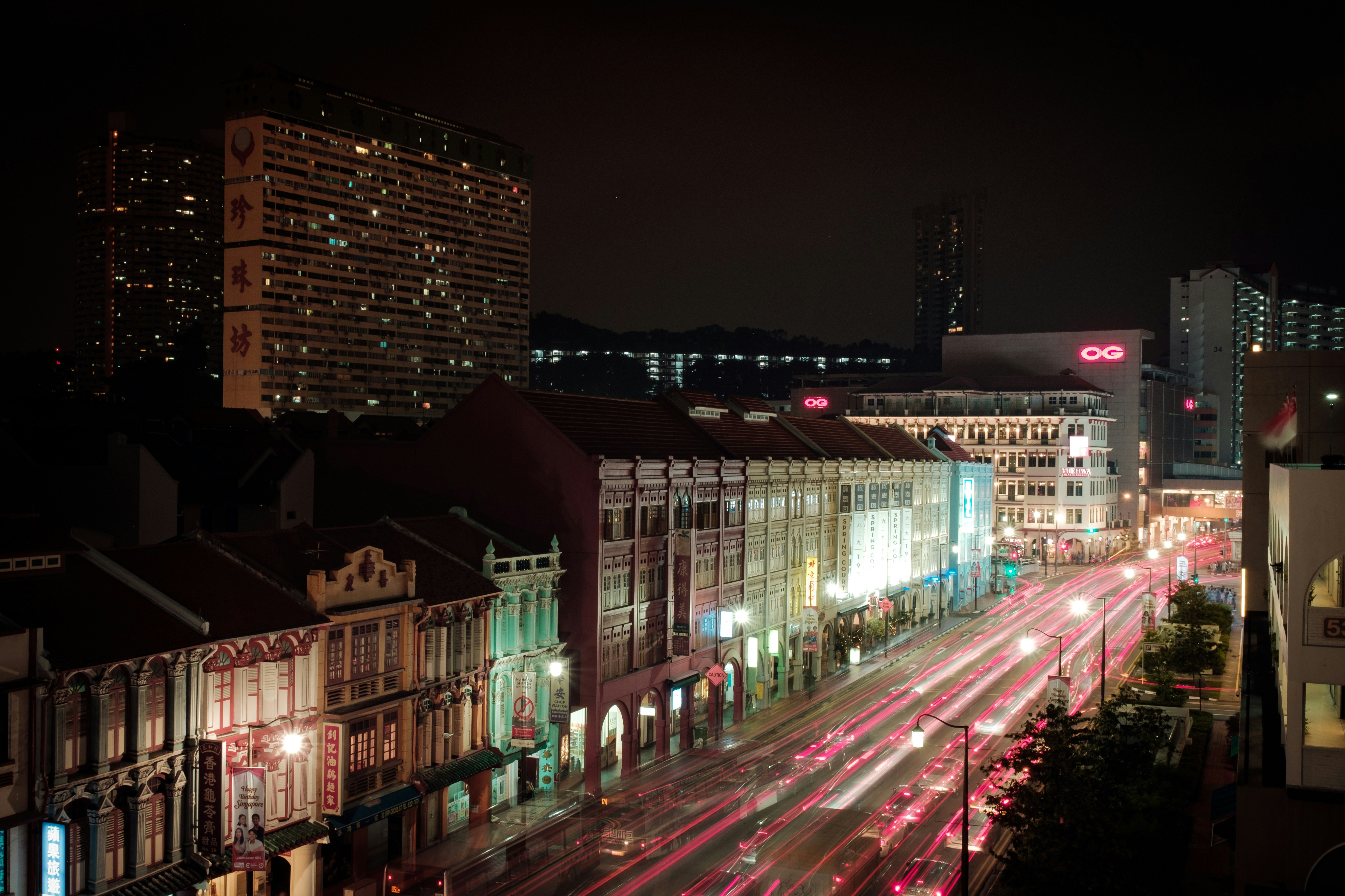 Vibrant city street illuminated by colorful lights and blurred traffic at night.