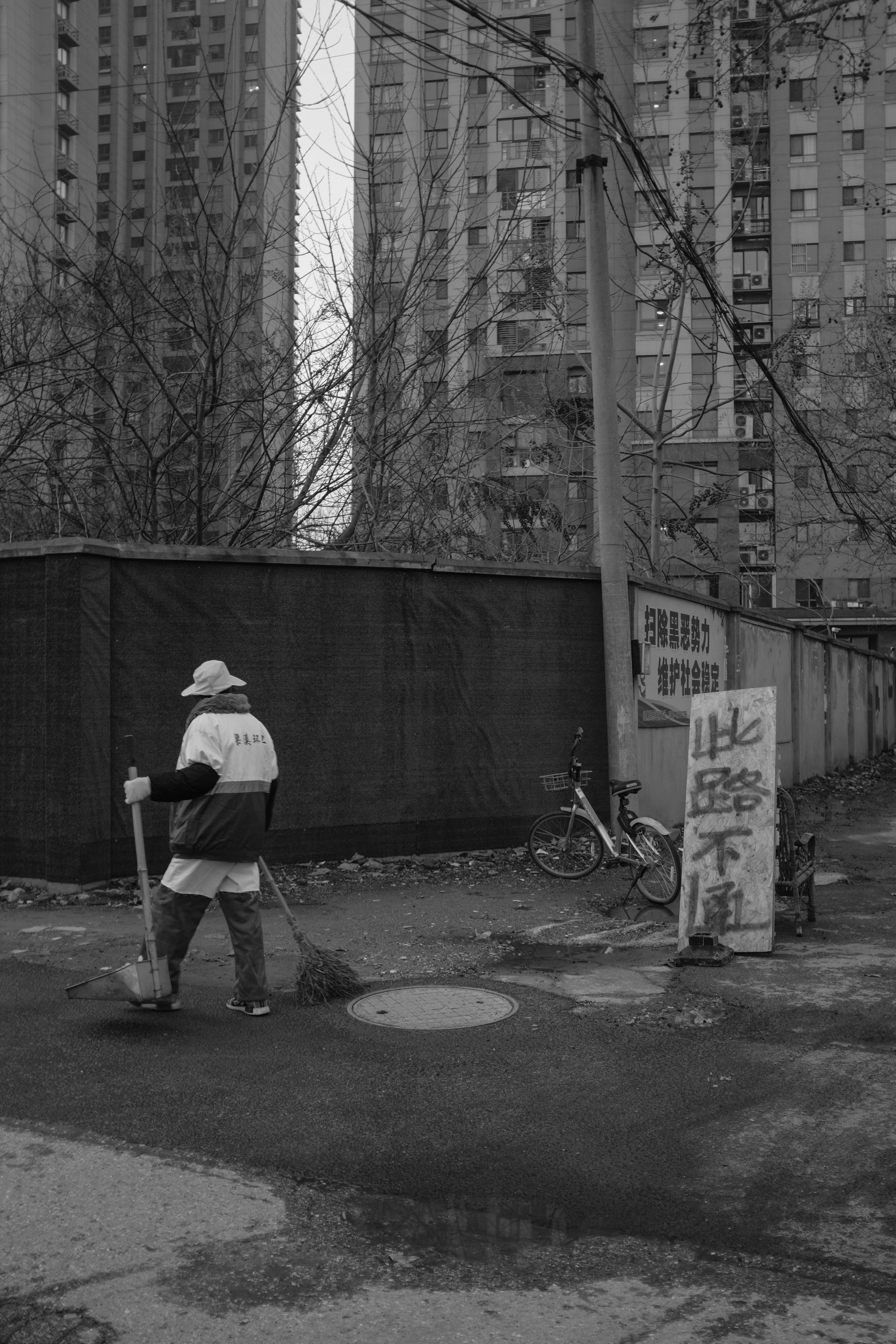 grayscale photo of man in white long sleeve shirt and black pants riding kick scooter