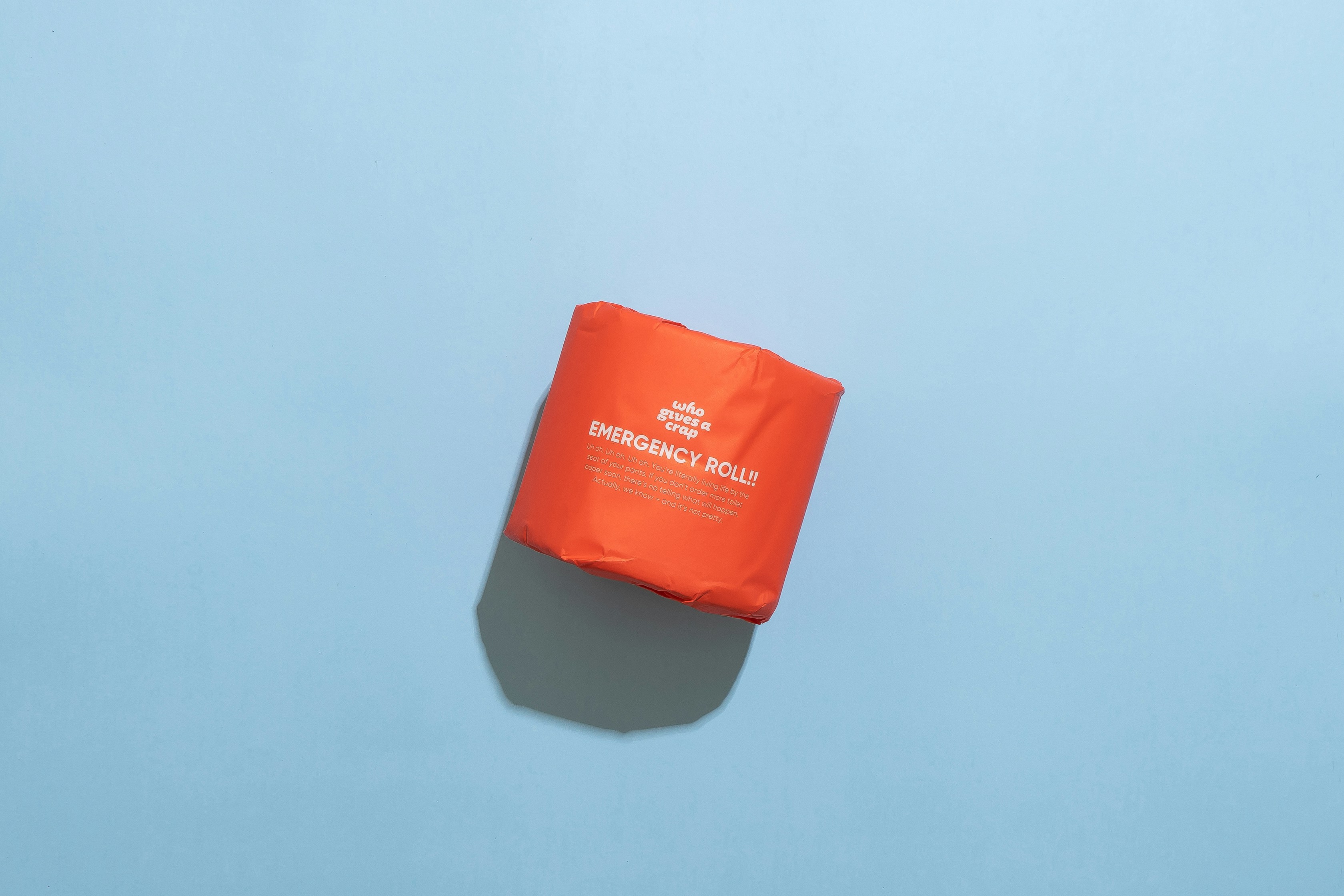 Bright orange emergency roll against a soft blue background, showcasing its packaging and text clearly.