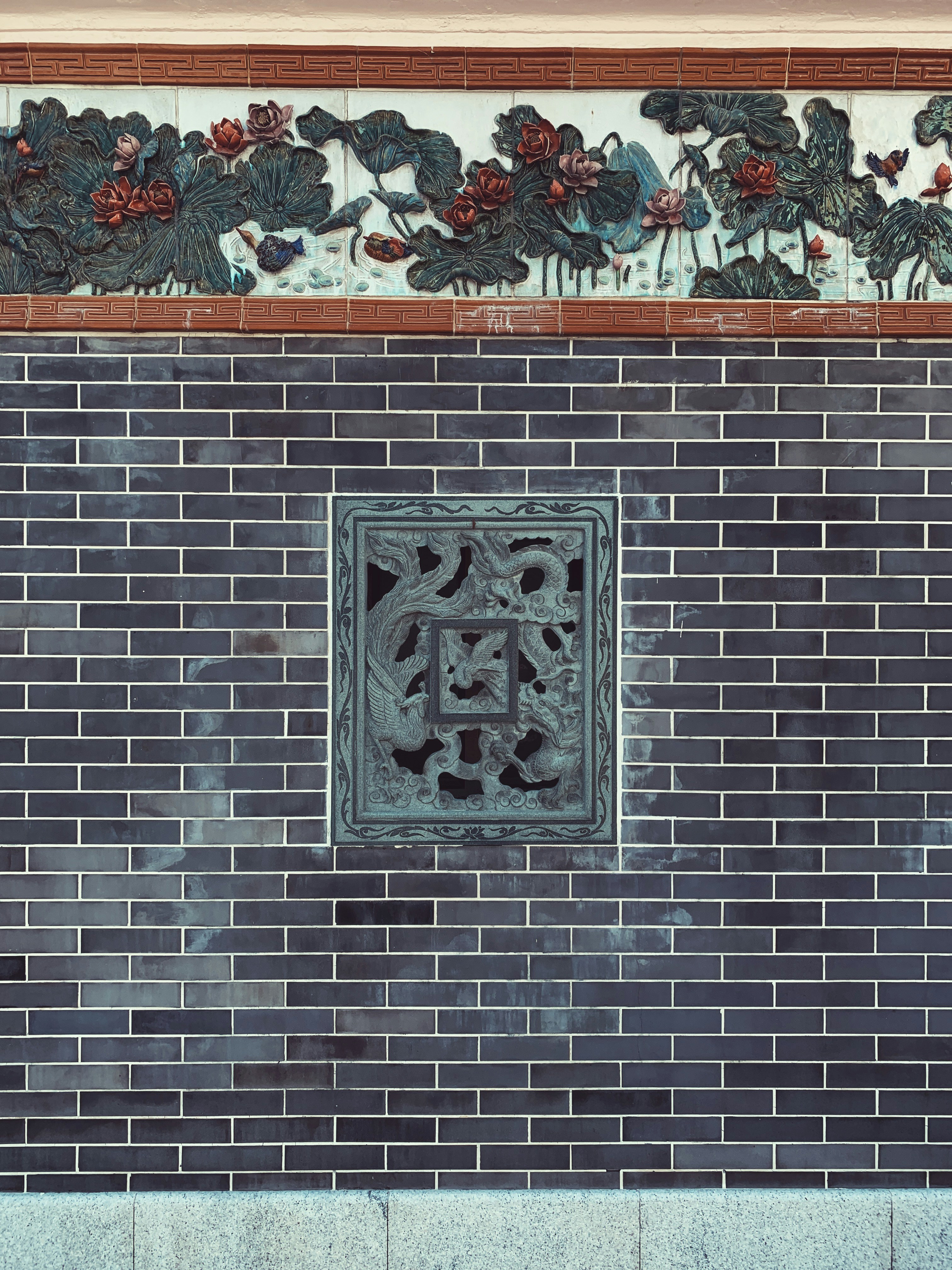 Ornate wall featuring a central relief sculpture framed by decorative tiles and floral motifs.