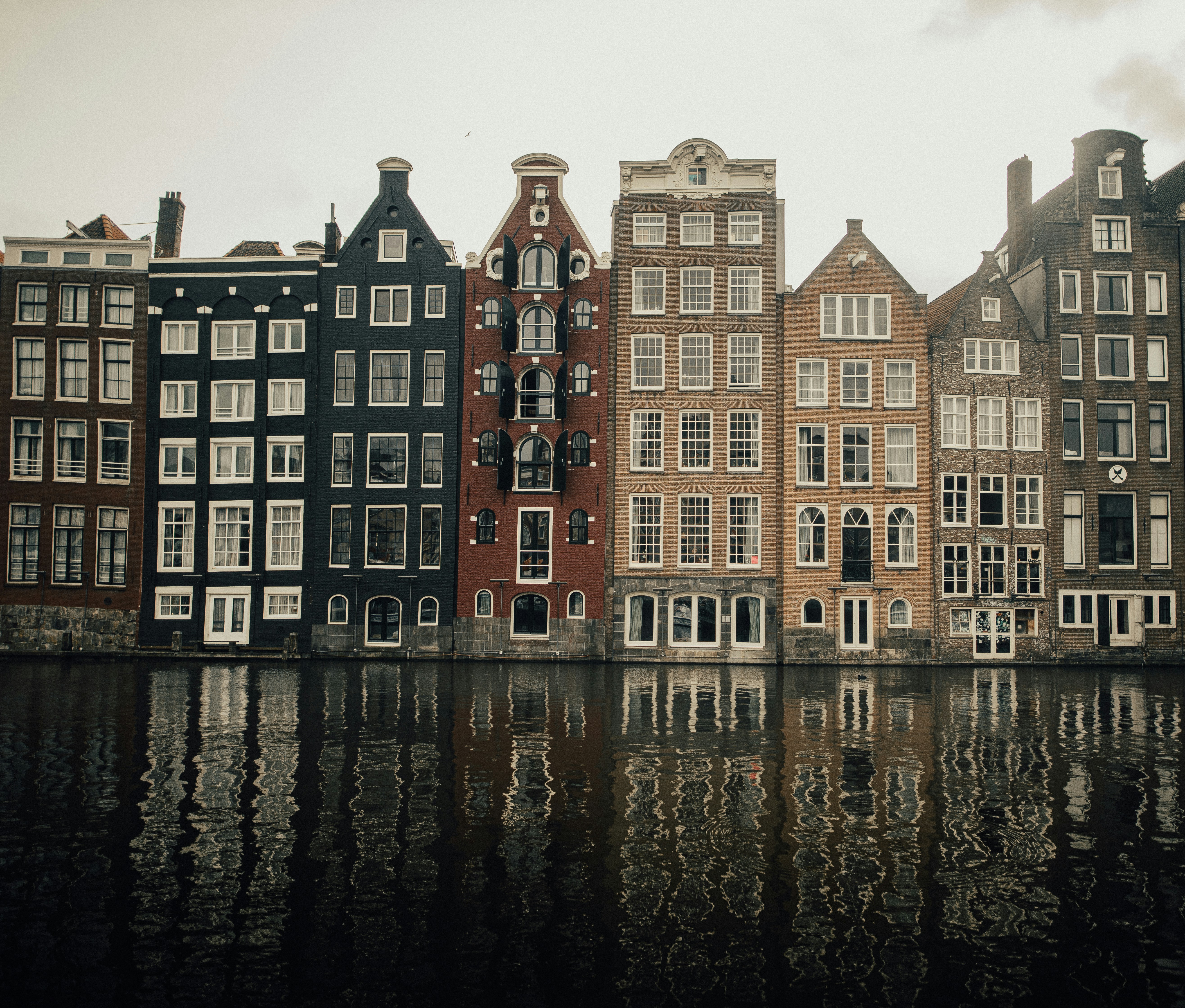 Colorful canal houses reflecting in still waters, showcasing the unique architecture of Amsterdam's historic district.