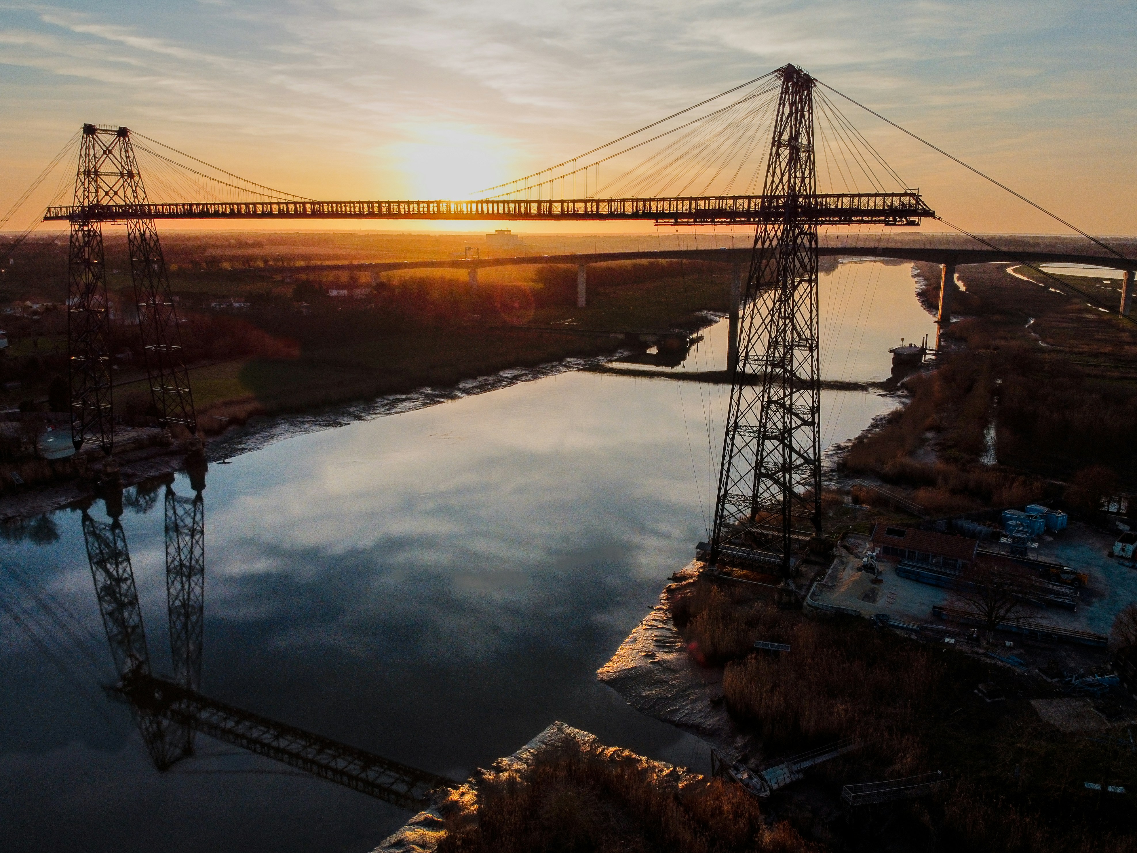 Dusk Span: Aerial Portrait of a Suspension Bridge Over the Quiet River