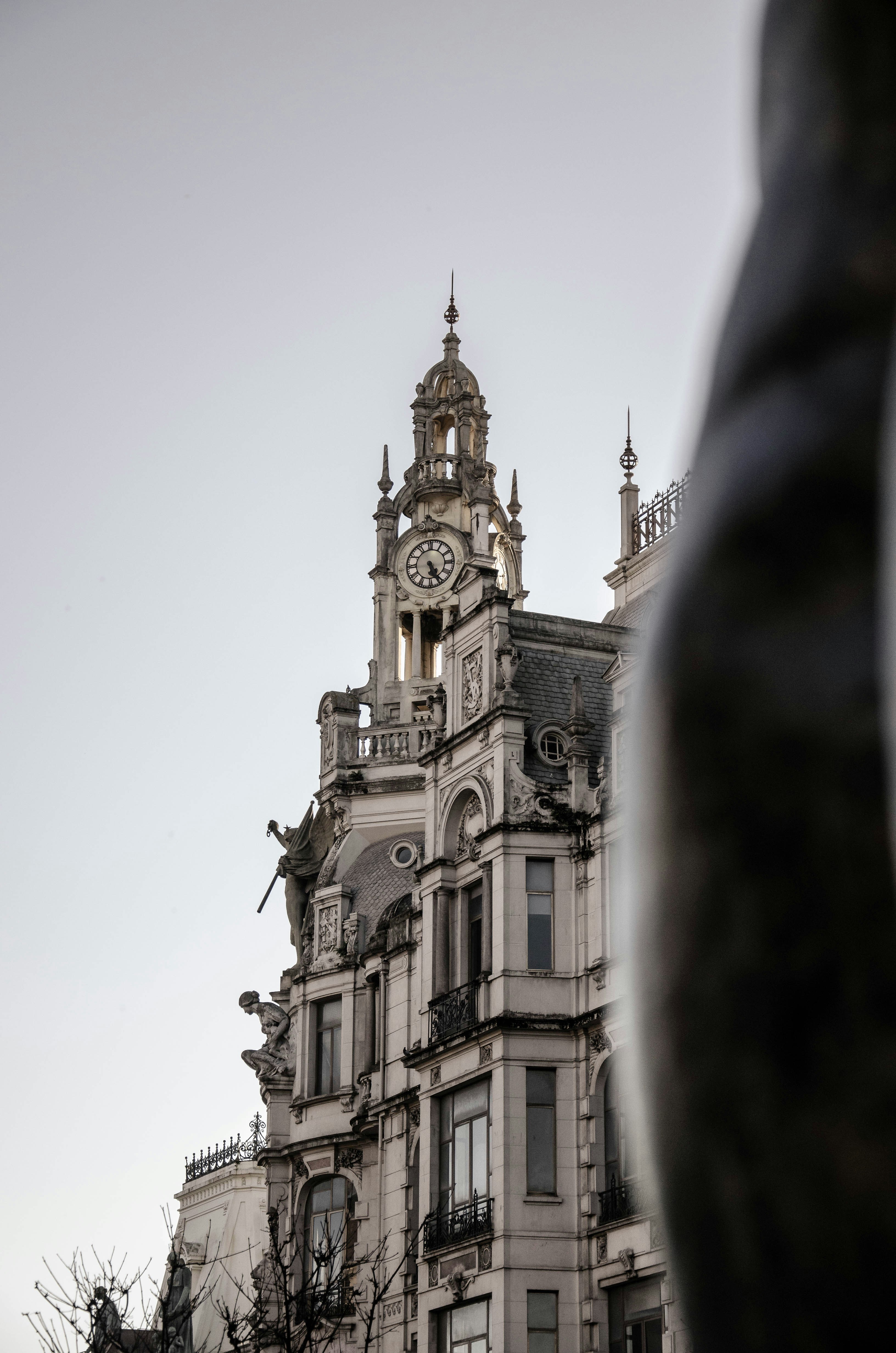 Historic building featuring an ornate clocktower against a pale sky, showcasing architectural details and grandeur.