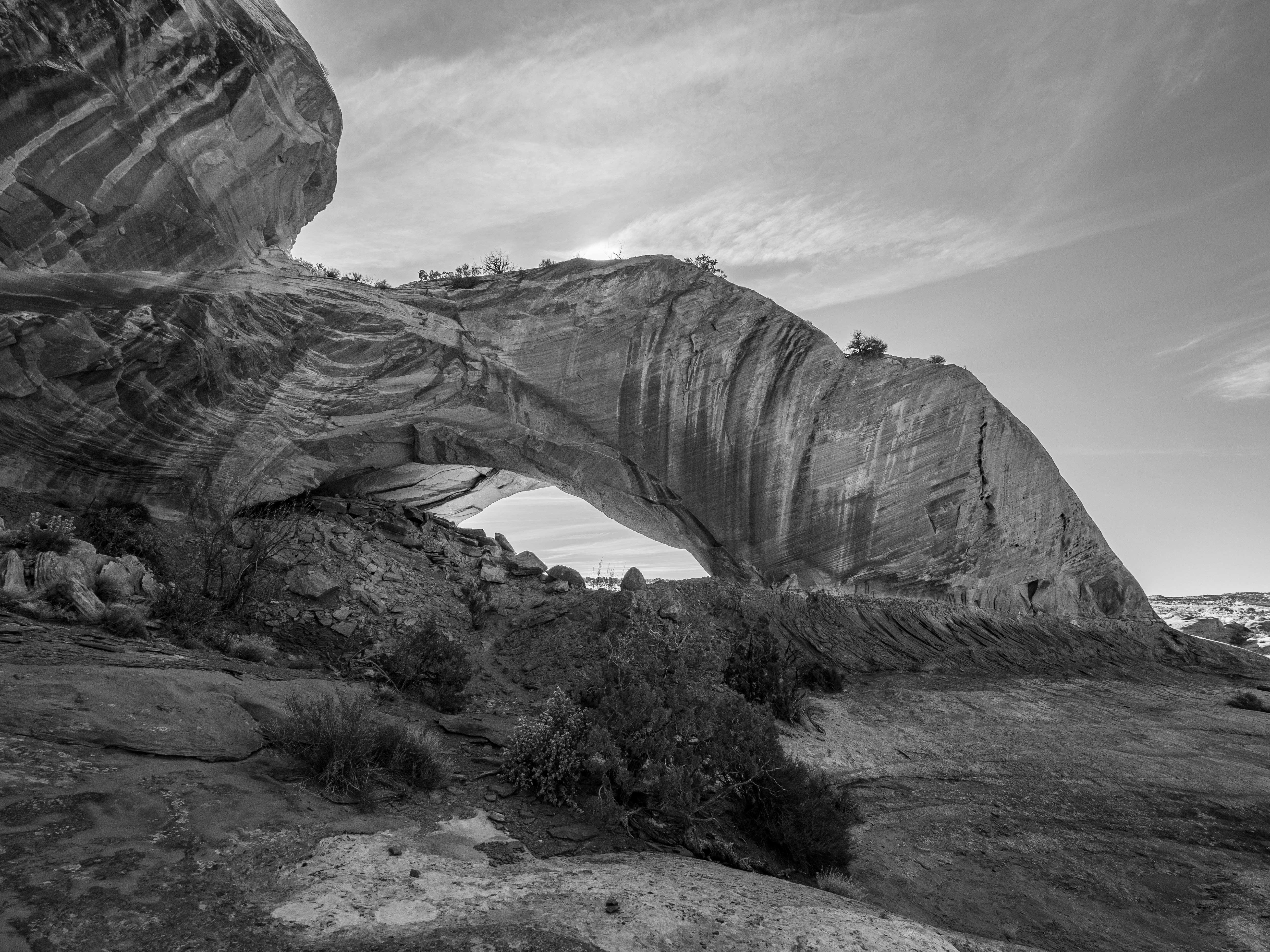 Monochrome Gateway: Desert Rock Arch Framed by Sparse Scrub