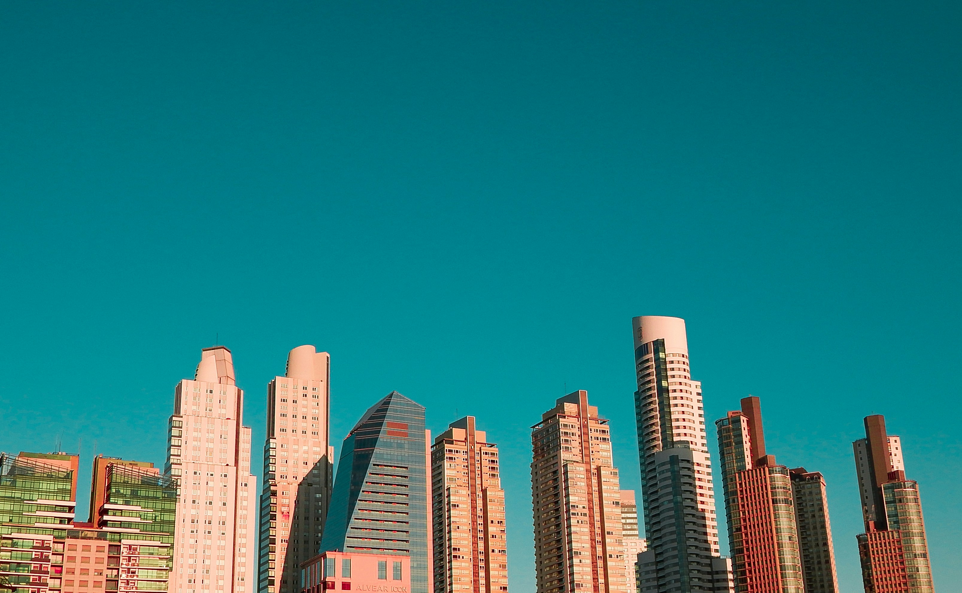 City skyline with diverse skyscrapers under a vibrant blue sky.