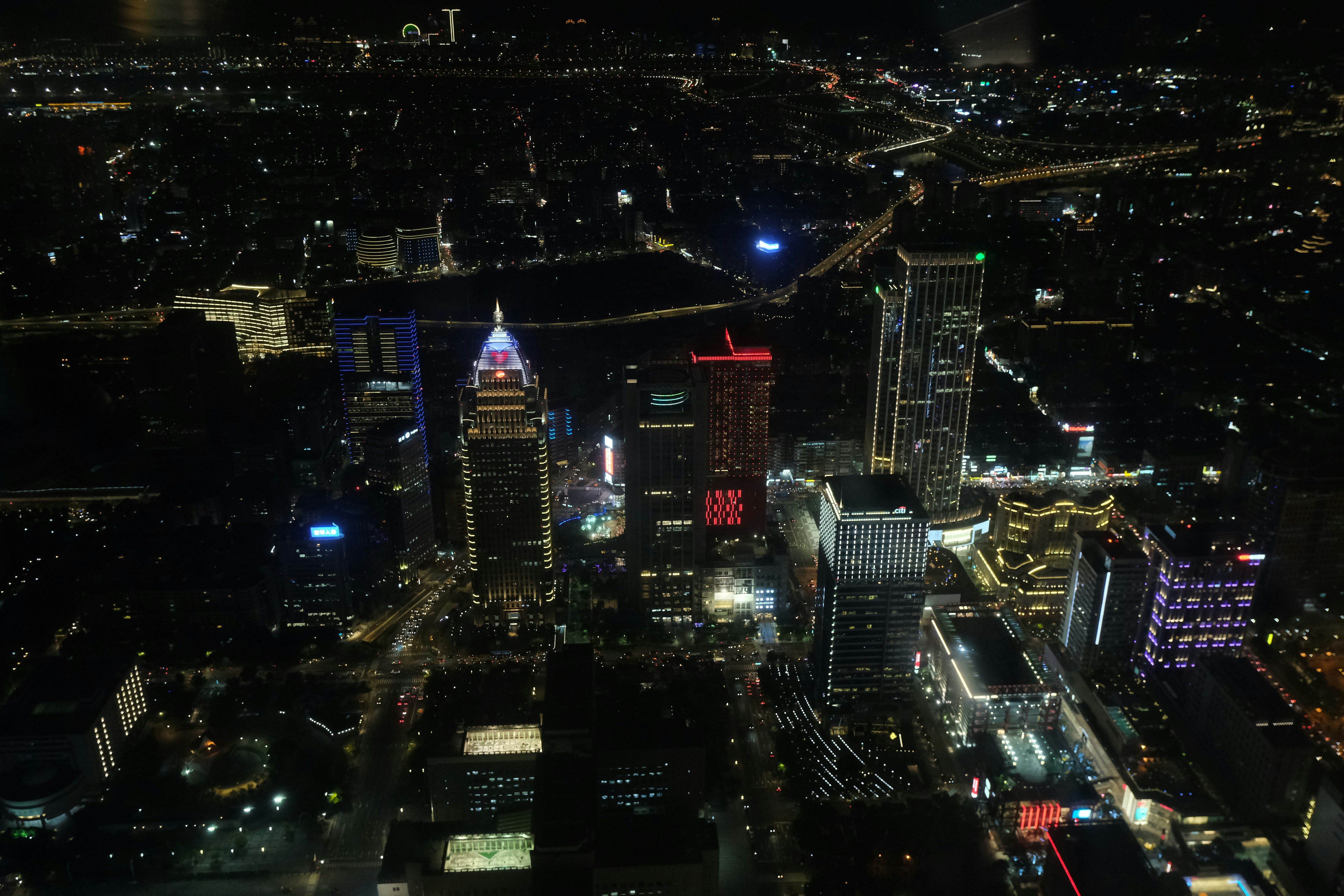 Aerial view of a city skyline illuminated by vibrant neon lights against the night sky.