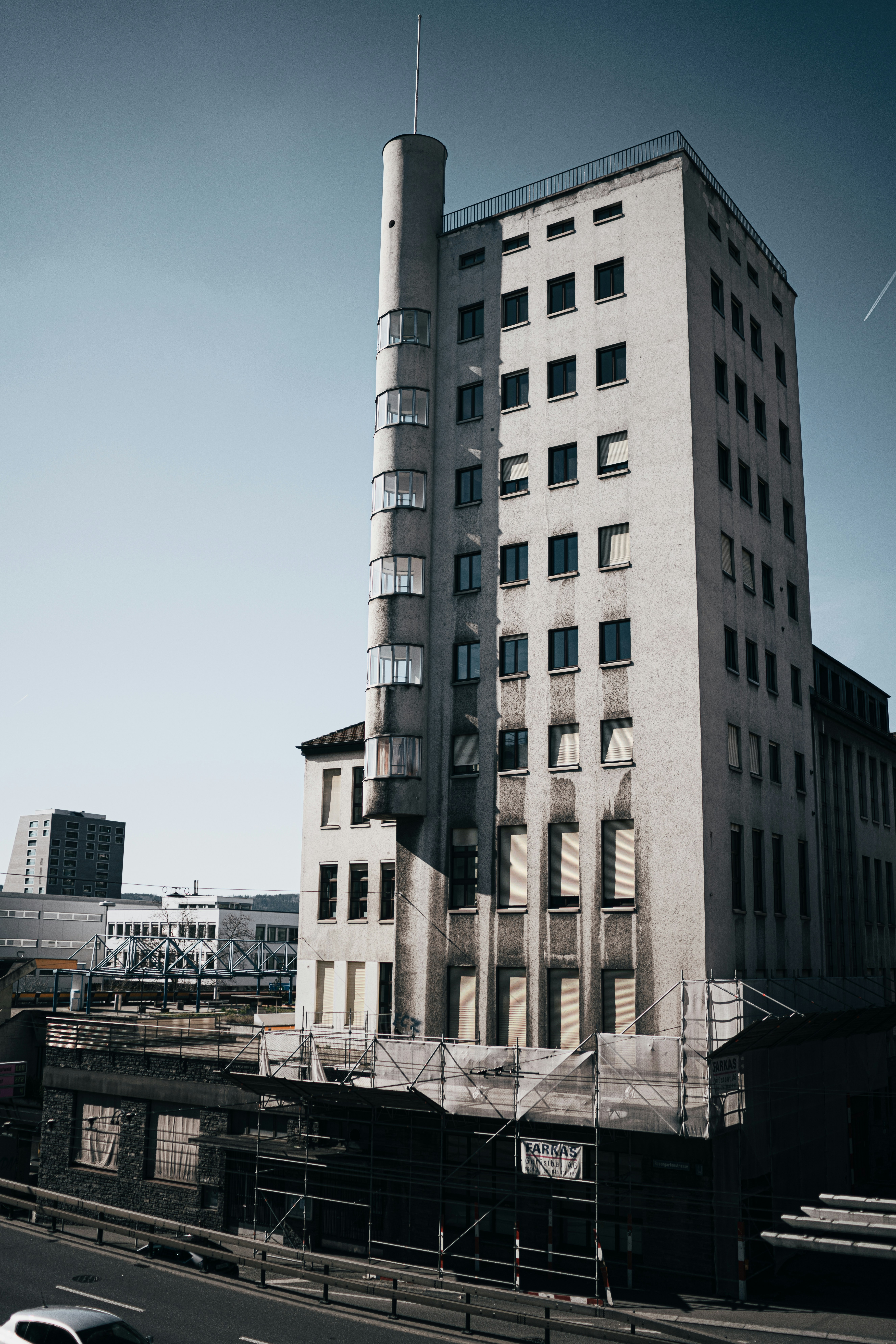 Sunlit Brutalist Tower: Cylindrical Stairwell Framing the Sky Above Scaffolding