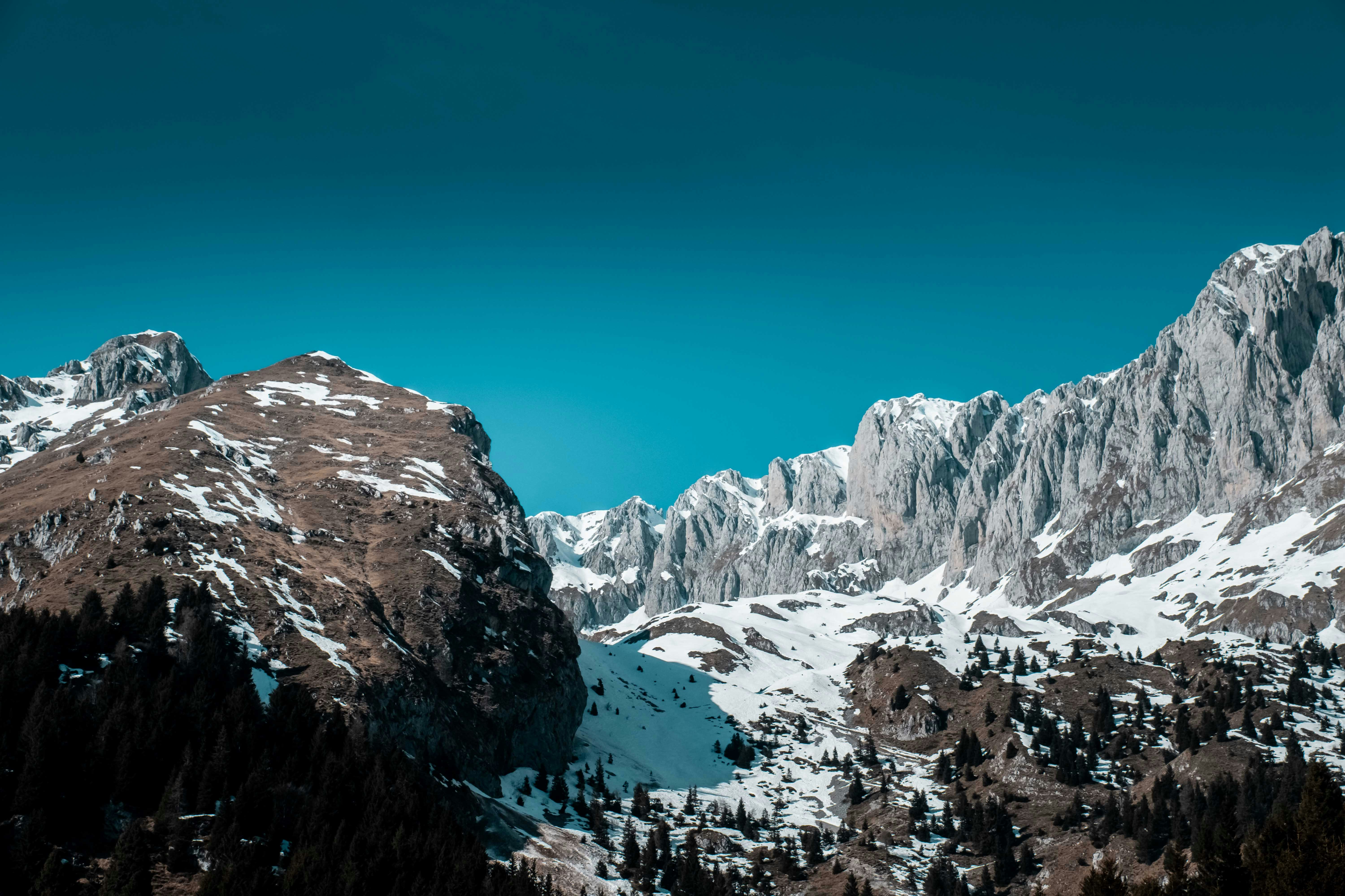 Snow-dusted mountains with rugged peaks against a deep blue sky.