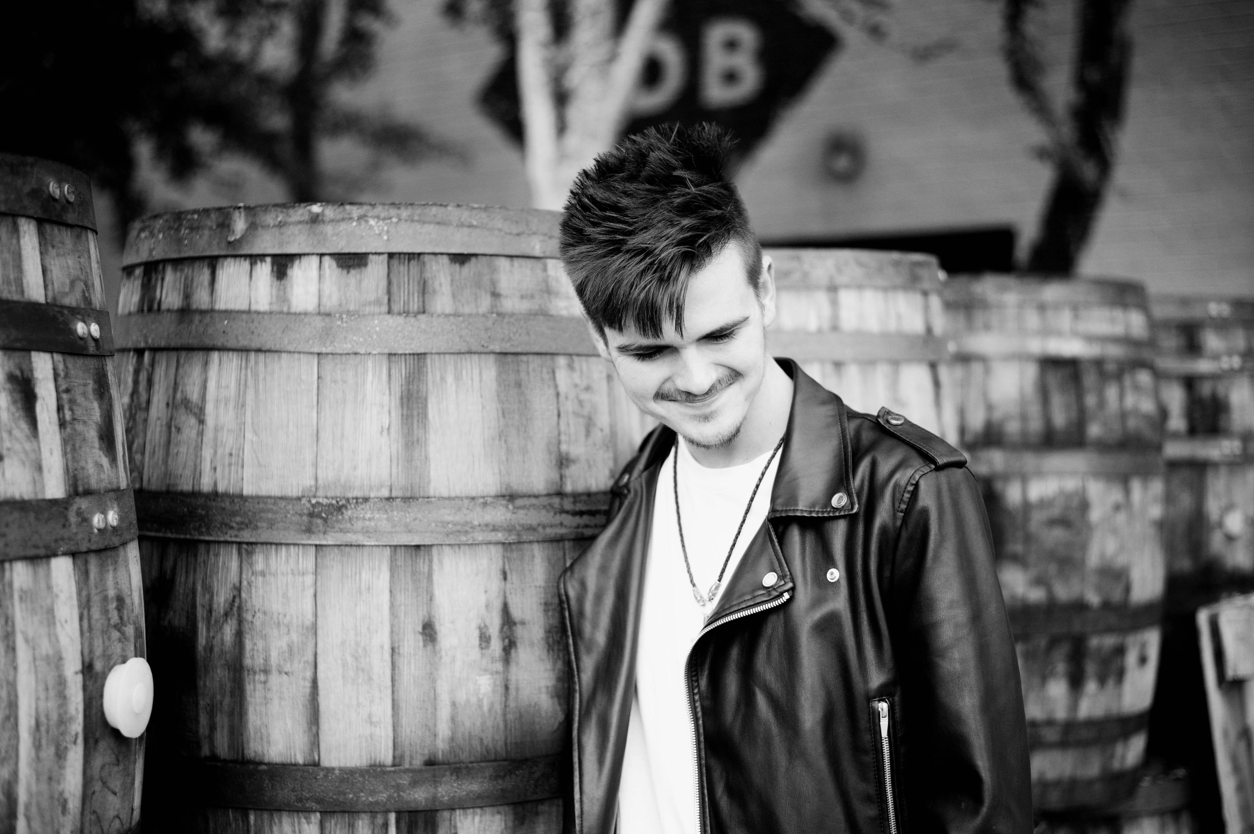 Monochrome Moment: Leather-Jacket Portrait Among Weathered Barrels
