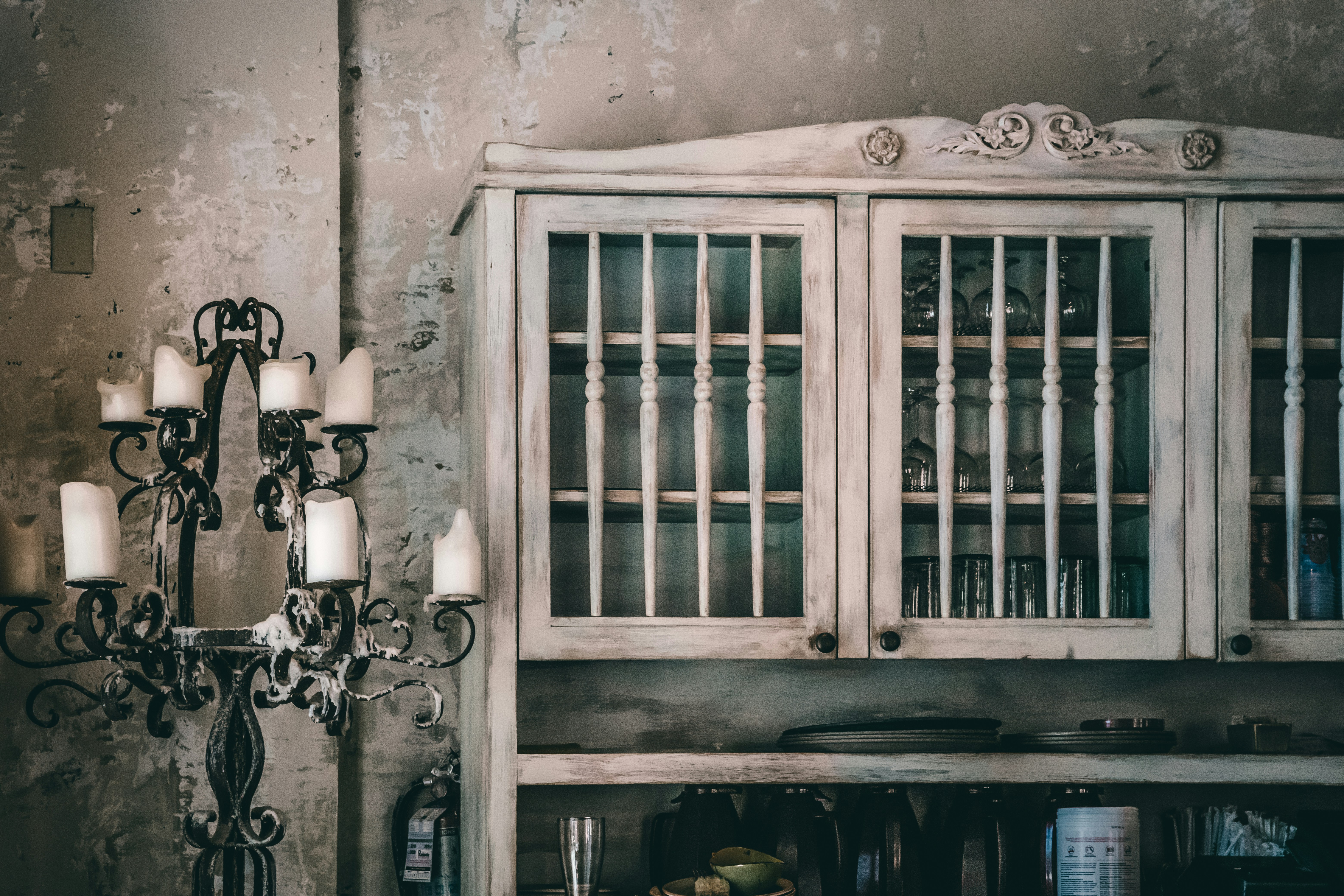 Weathered display: an antique cabinet flanked by a wrought-iron candelabrum