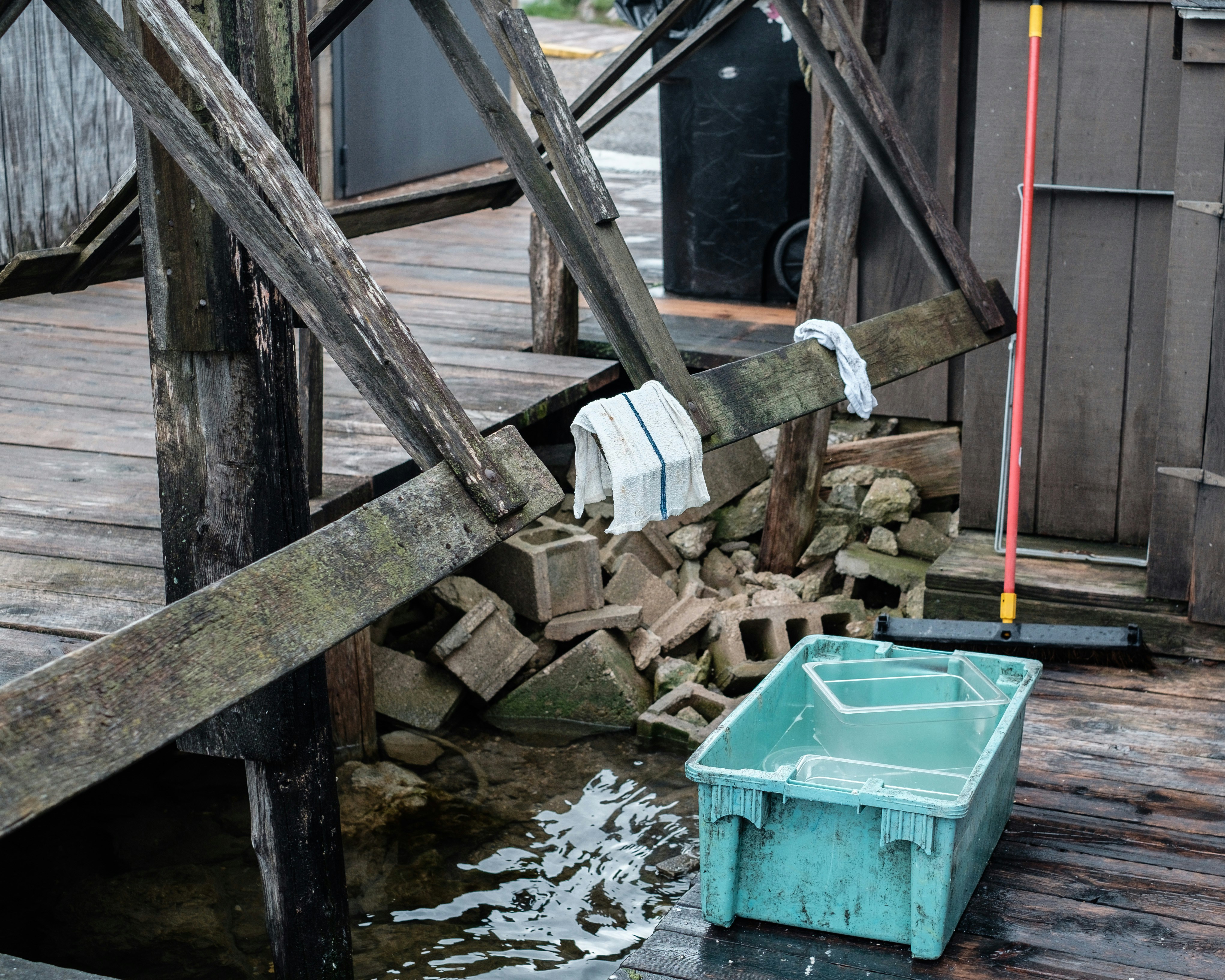 Teal Bin at the Tide-Worn Dock: Weathered Wood and Quiet Clutter