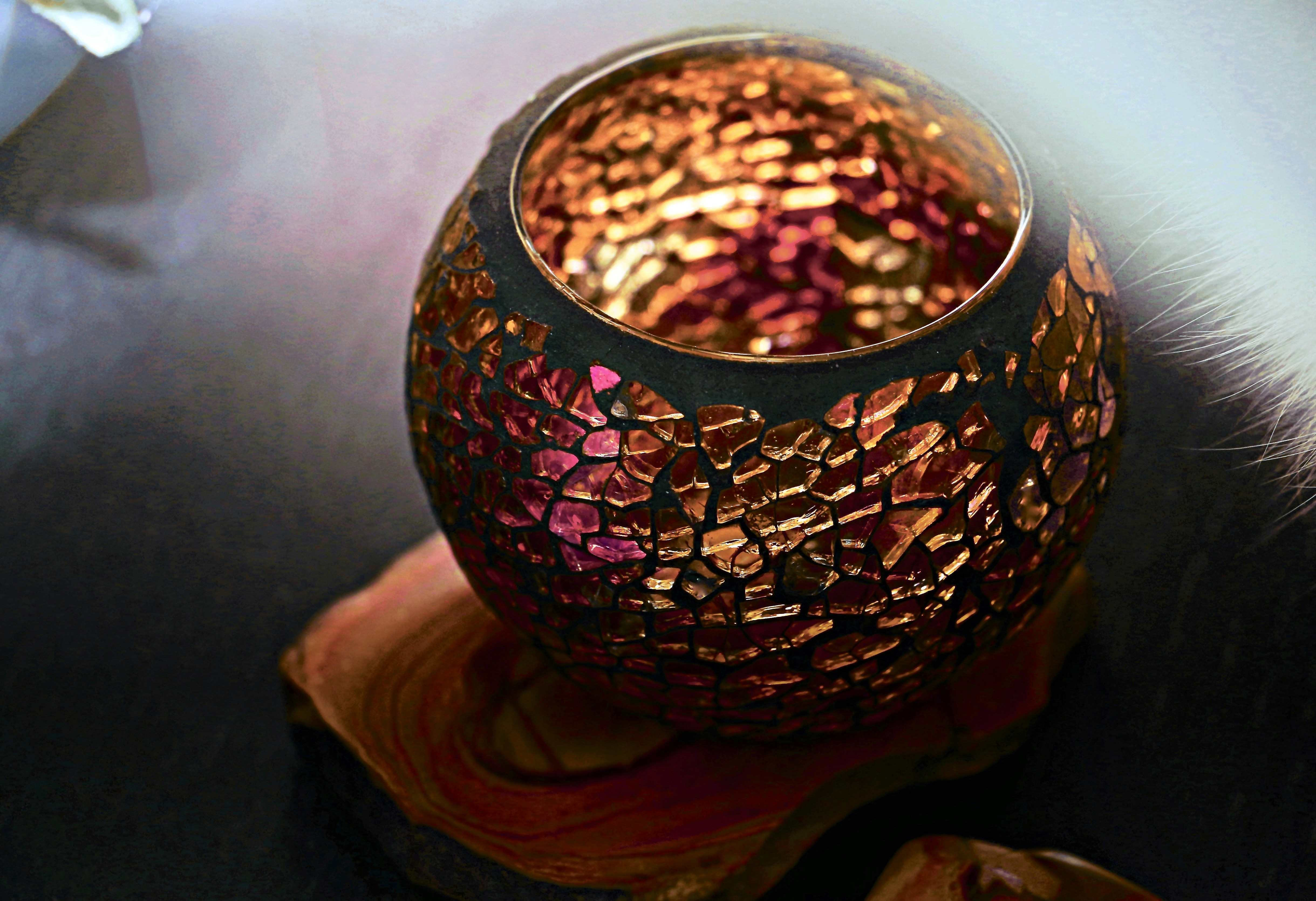 Intricately designed mosaic candle holder casting warm hues on a natural stone base.