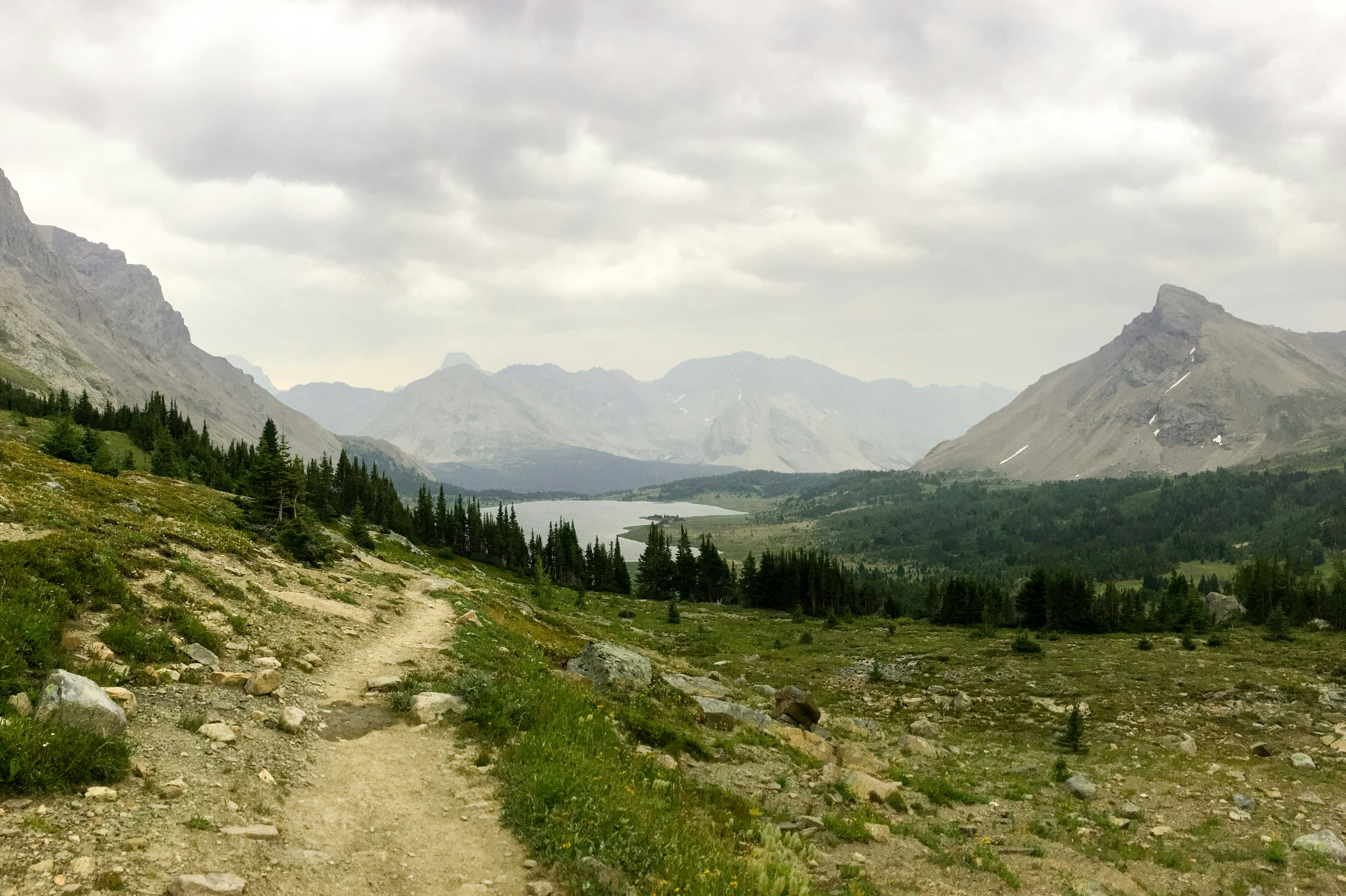 Un chemin de terre menant à un lac entouré de montagnes photo – Photo ...