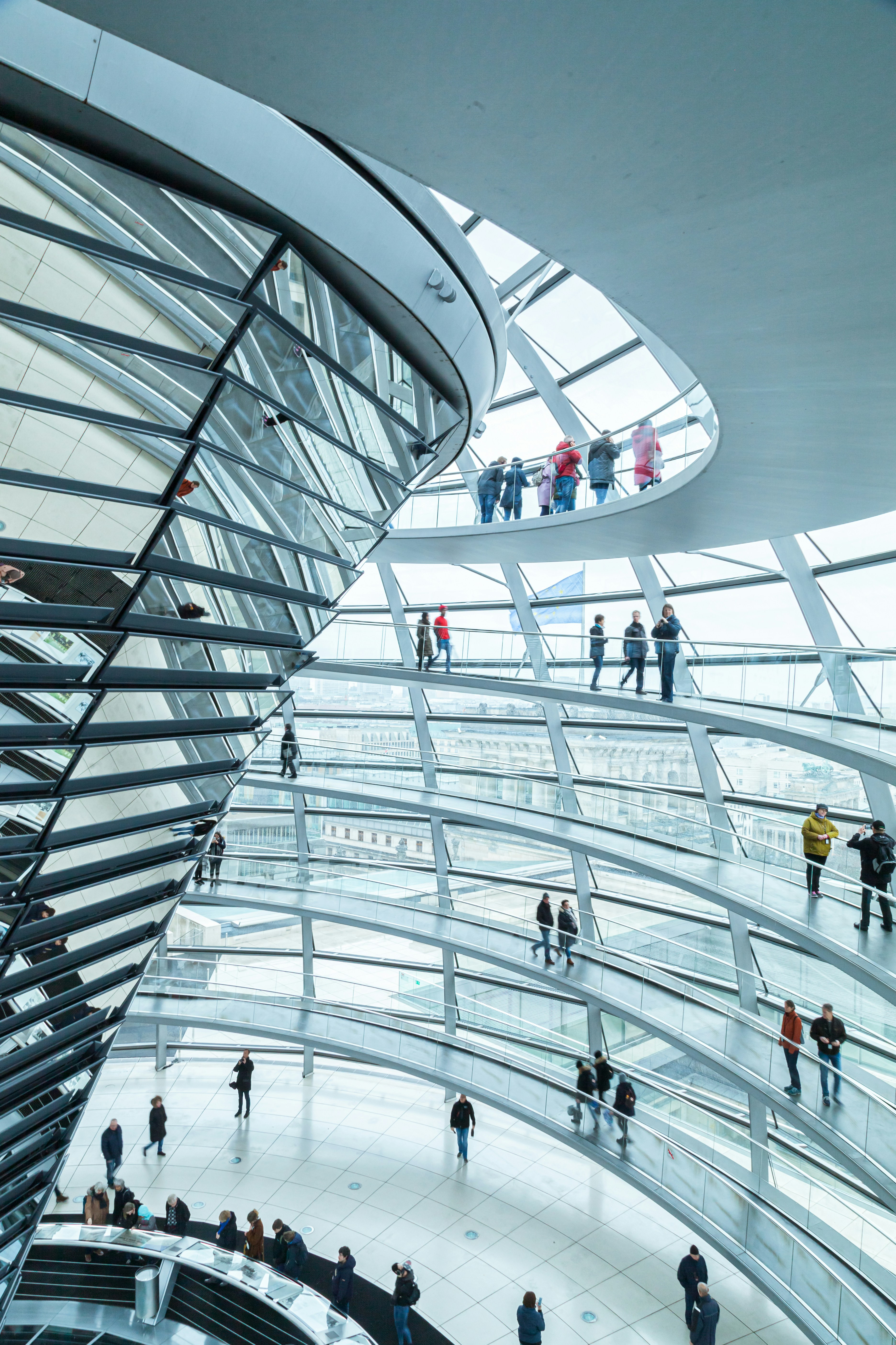 Few people and tourists walking on the spiral walkway of the dome on the berlin parliament | a group of people standing inside of a building