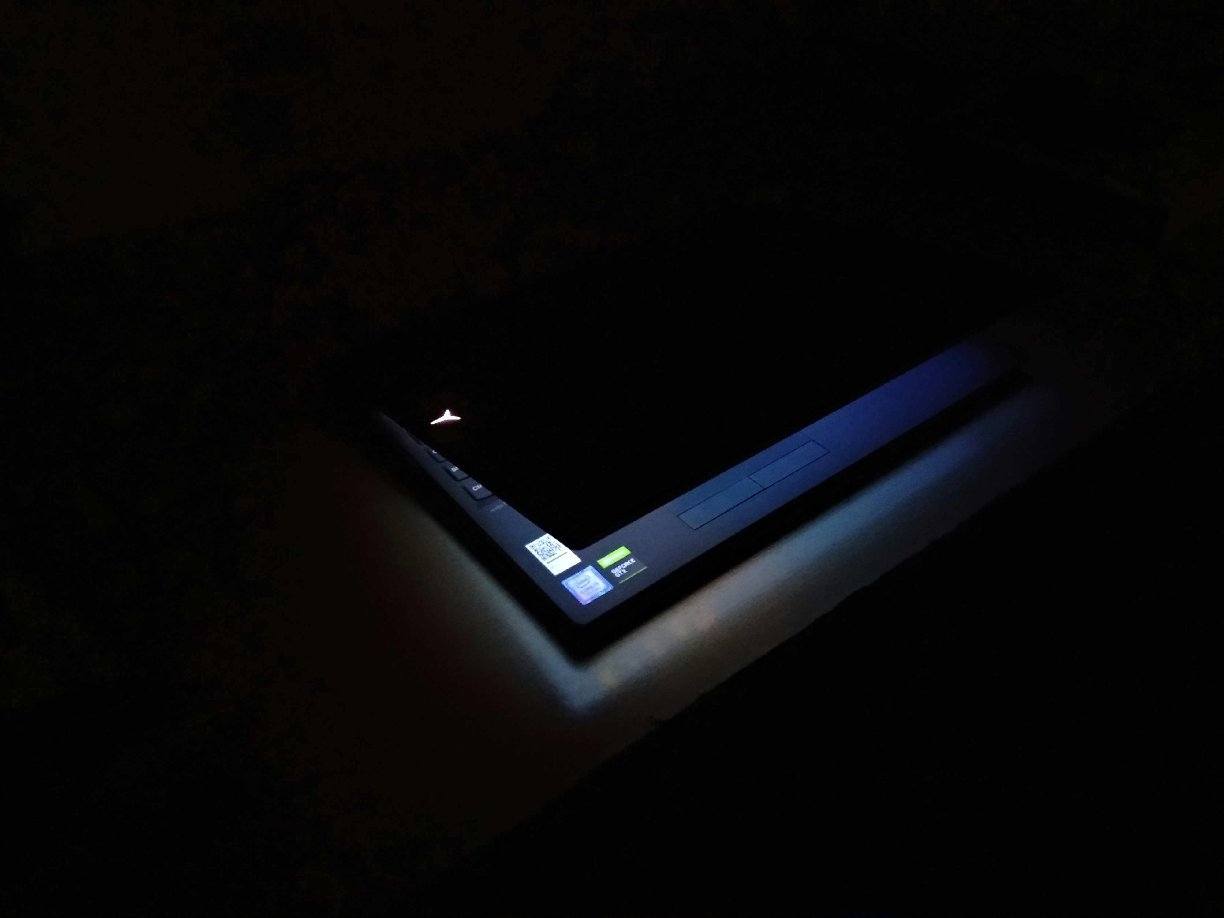 A sleek electronic device glows softly against a dark background, showcasing its illuminated screen and minimalistic design.