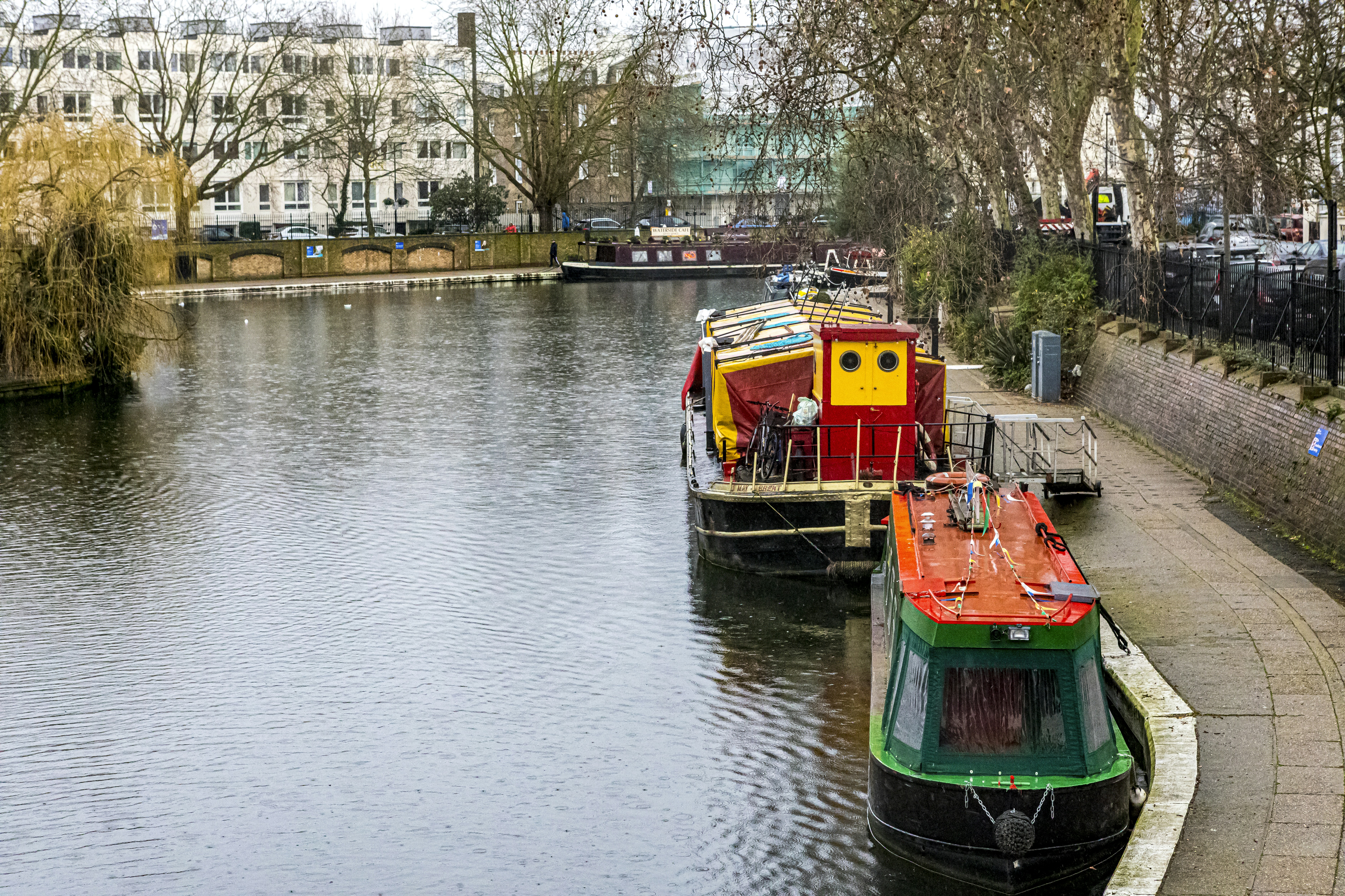 Red-Panel Houseboat with a Yellow Front Anchors a Serene Canal