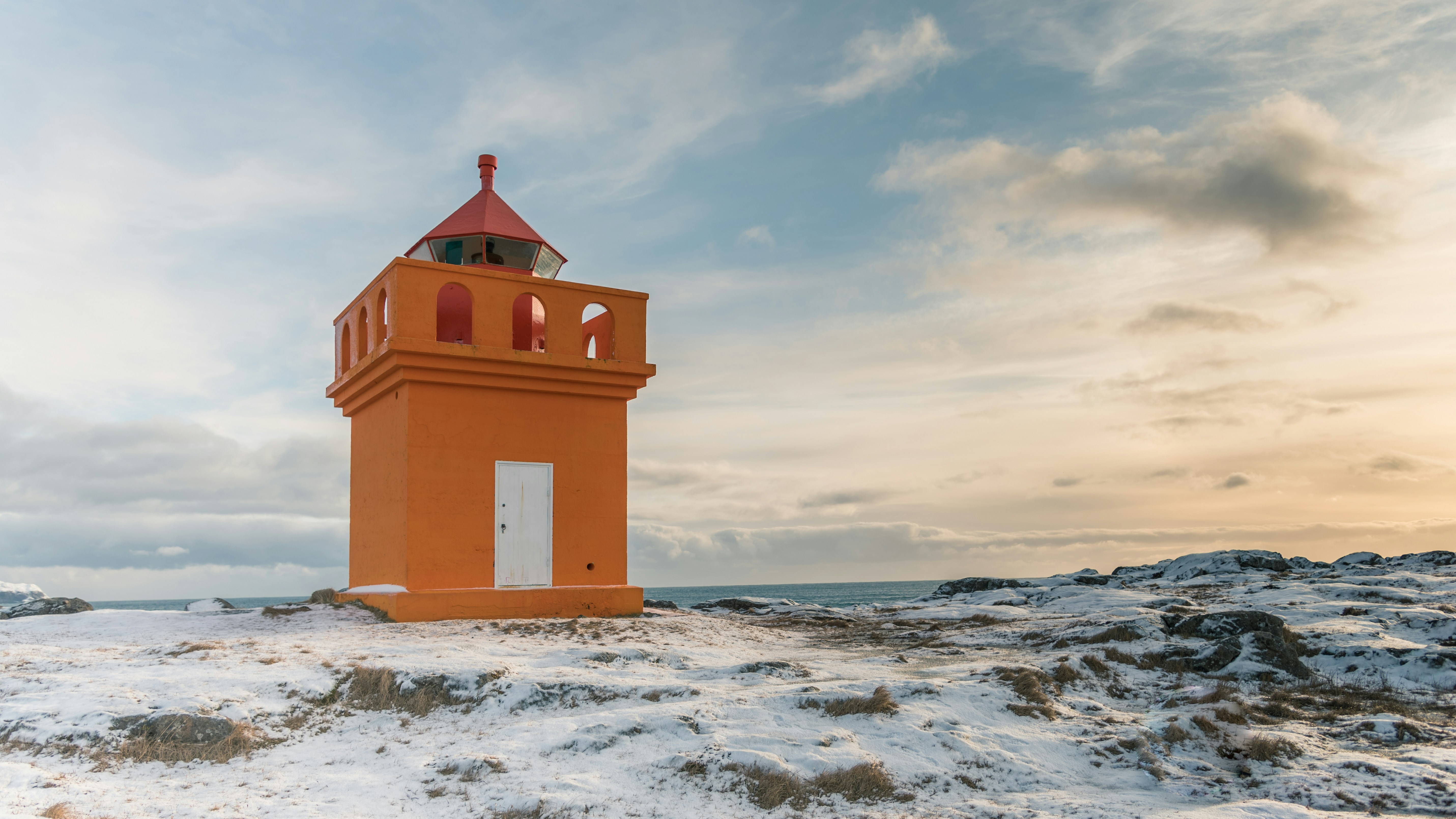 A small orange lighthouse on the east coast of Iceland