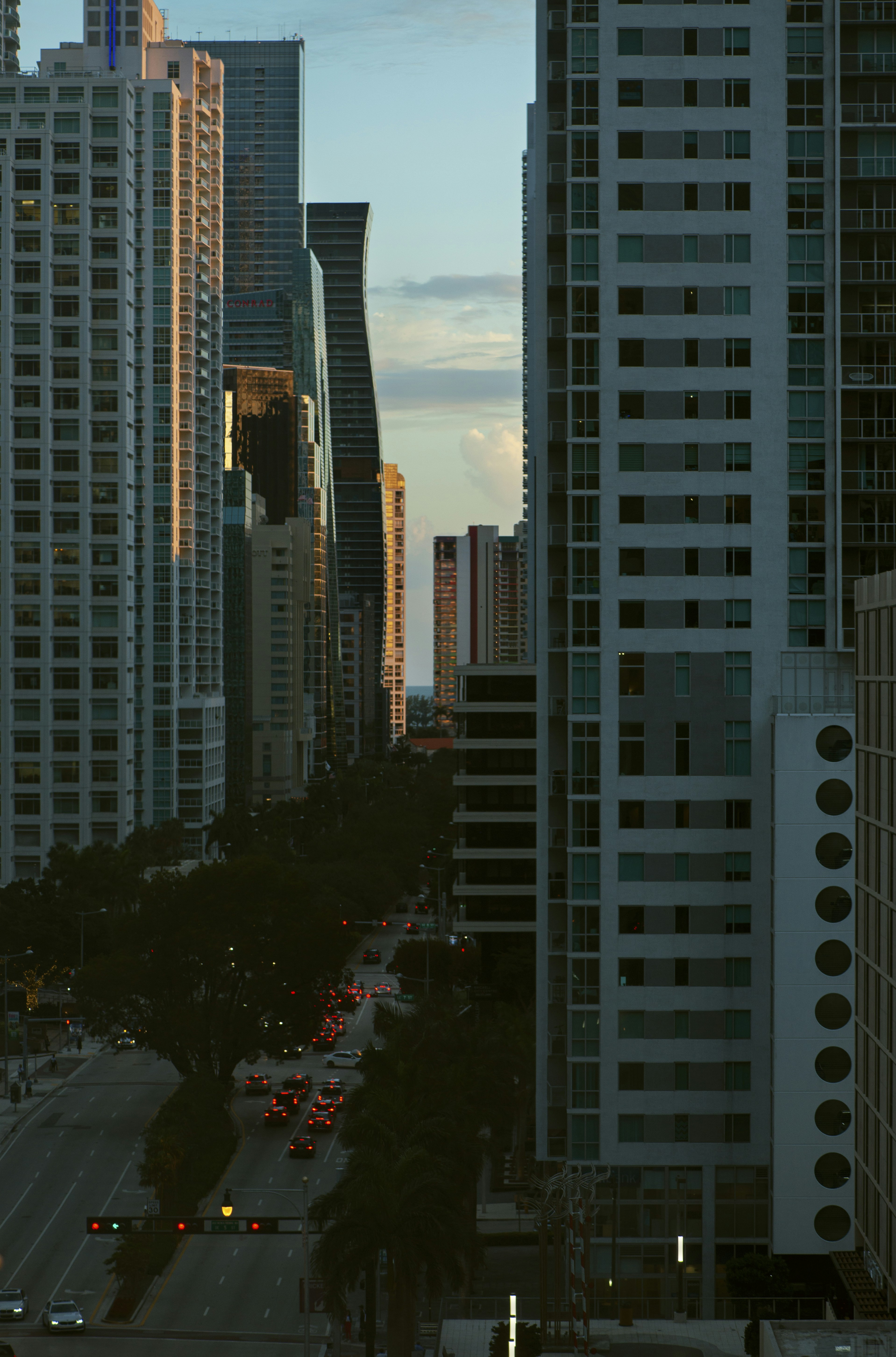 City skyline featuring a mix of modern skyscrapers and bustling streets illuminated by evening lights.