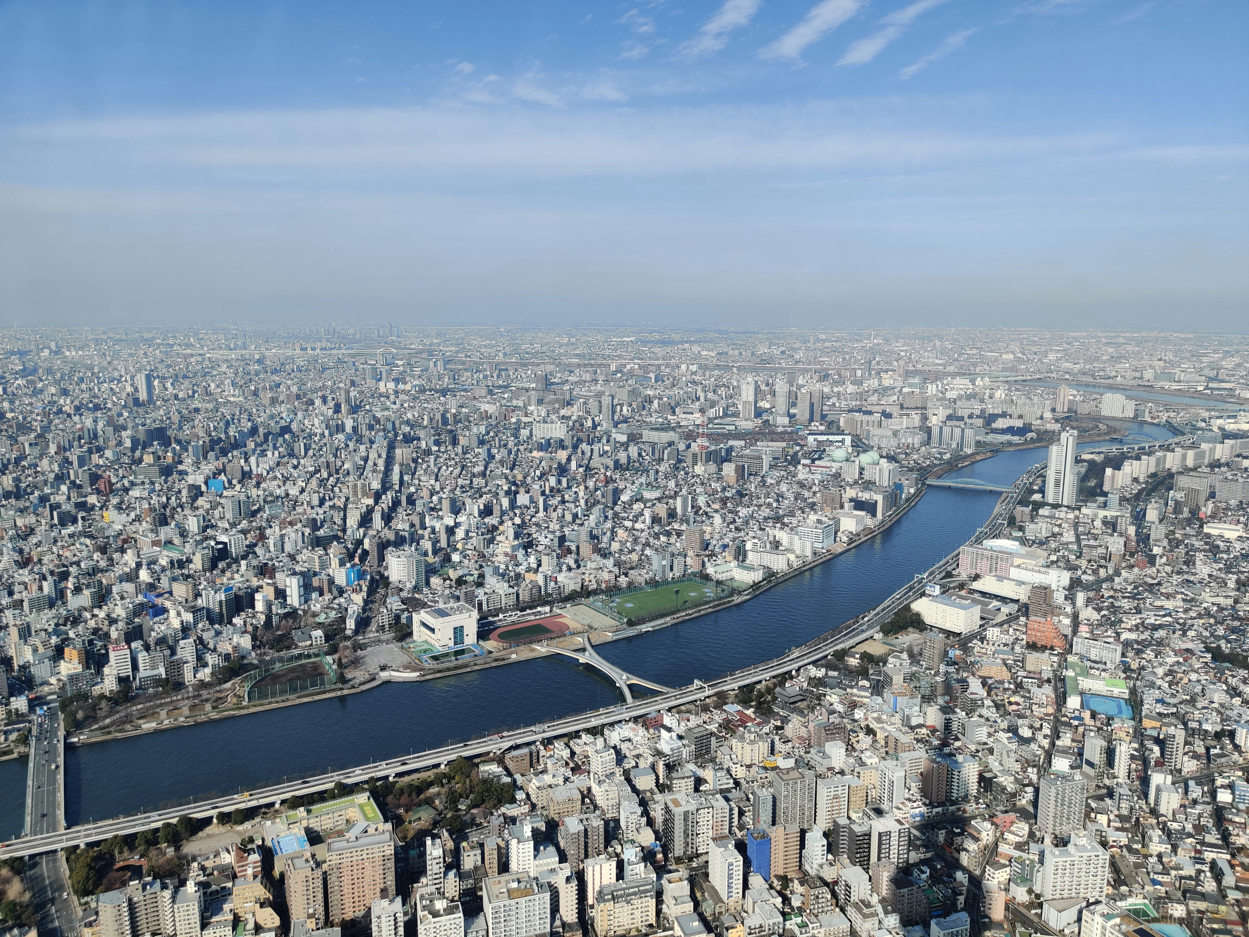Aerial photograph of a dense urban landscape with a winding river and multiple bridges slicing through the grid of buildings.