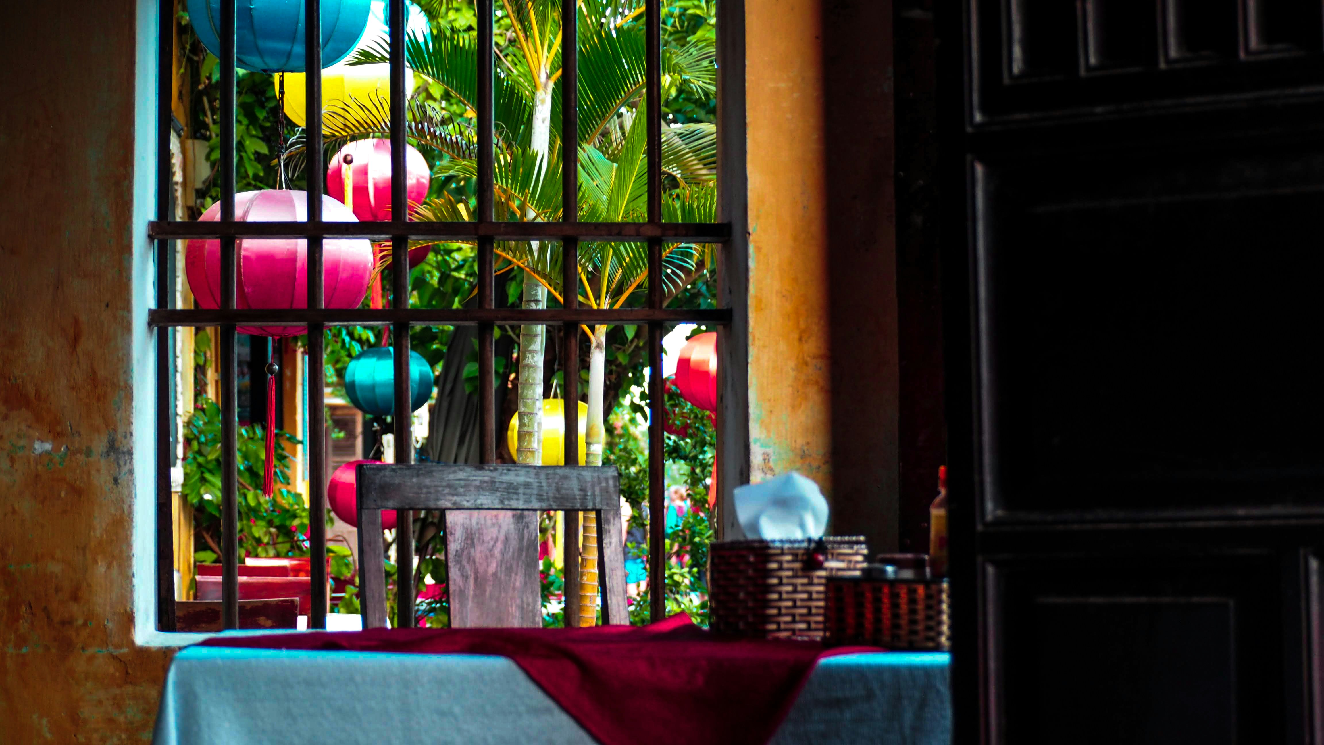 Table with red and white polka dot cloth by a window overlooking colorful outdoor lanterns.