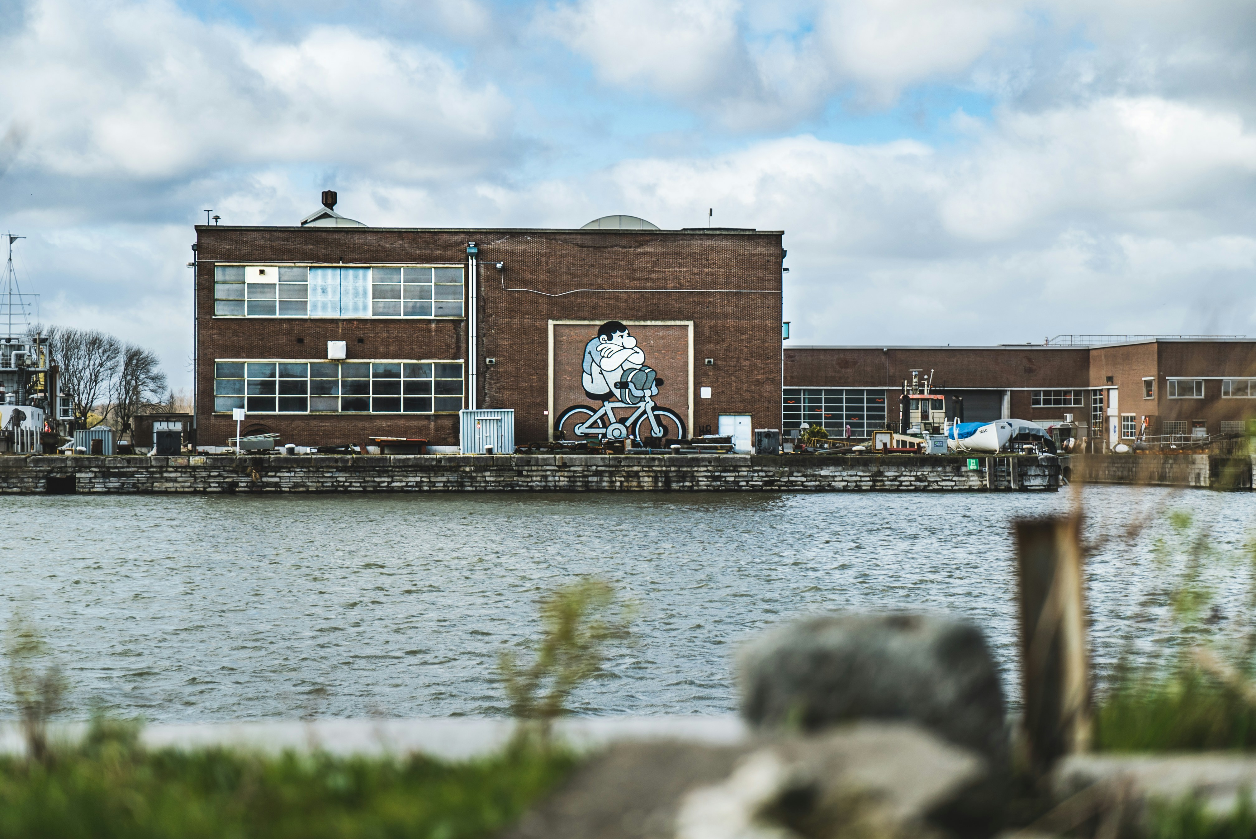 Cyclist mural on brick industrial backdrop across the river