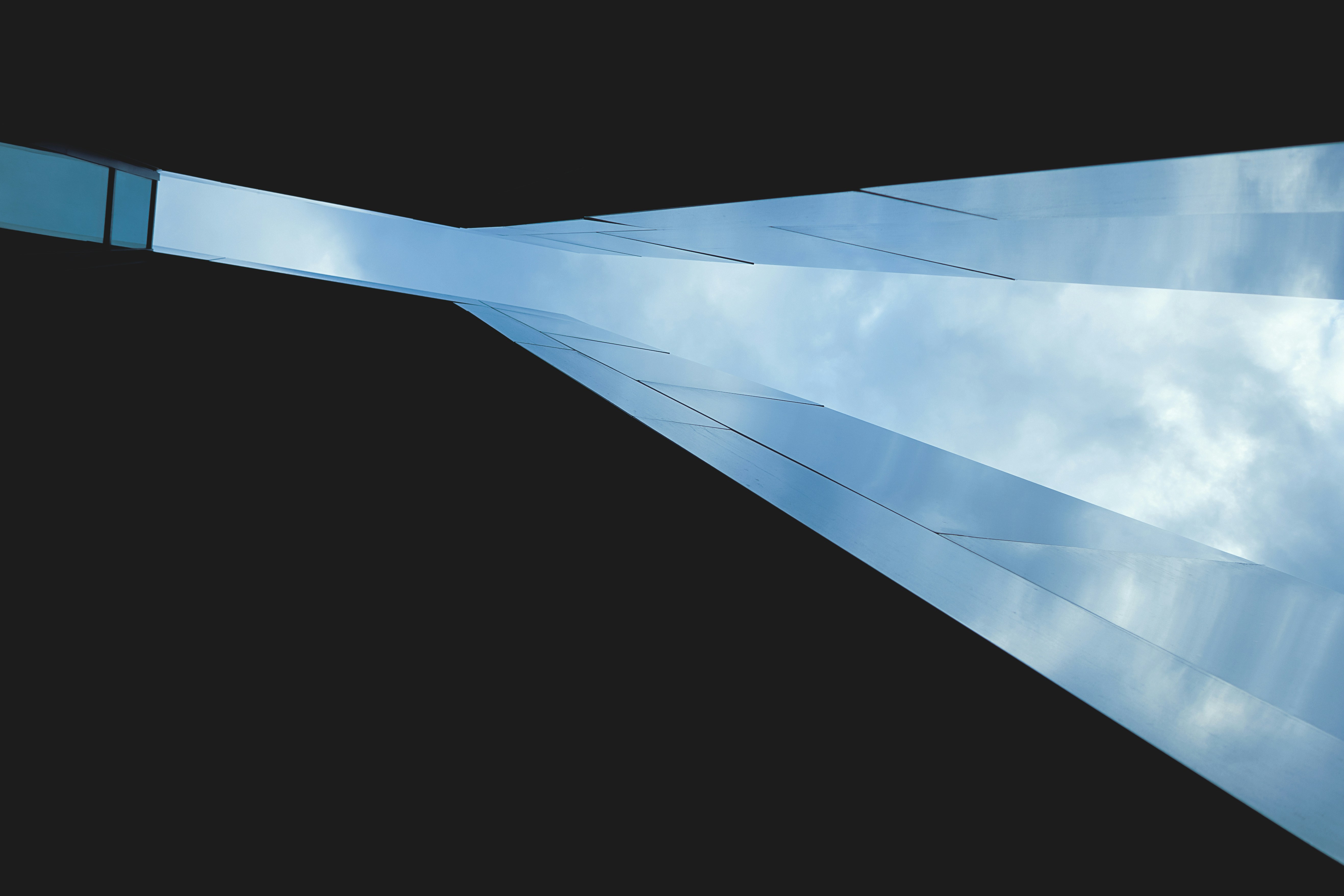 Abstract geometric shapes converging towards a bright sky, creating a sense of depth and perspective.