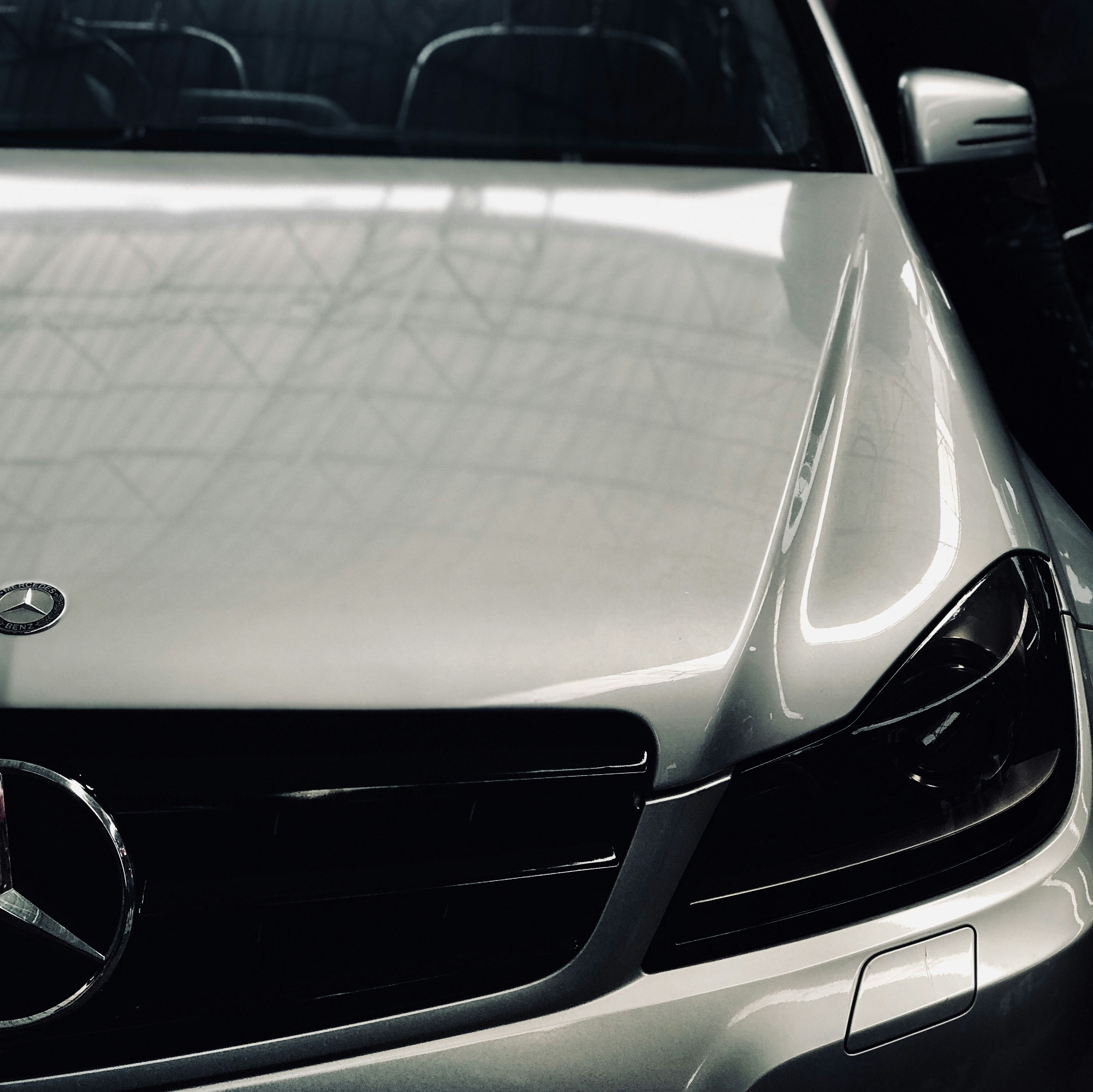 Sleek front view of a Mercedes-Benz vehicle showcasing its polished surface and iconic logo. The image highlights the car's luxurious design elements.