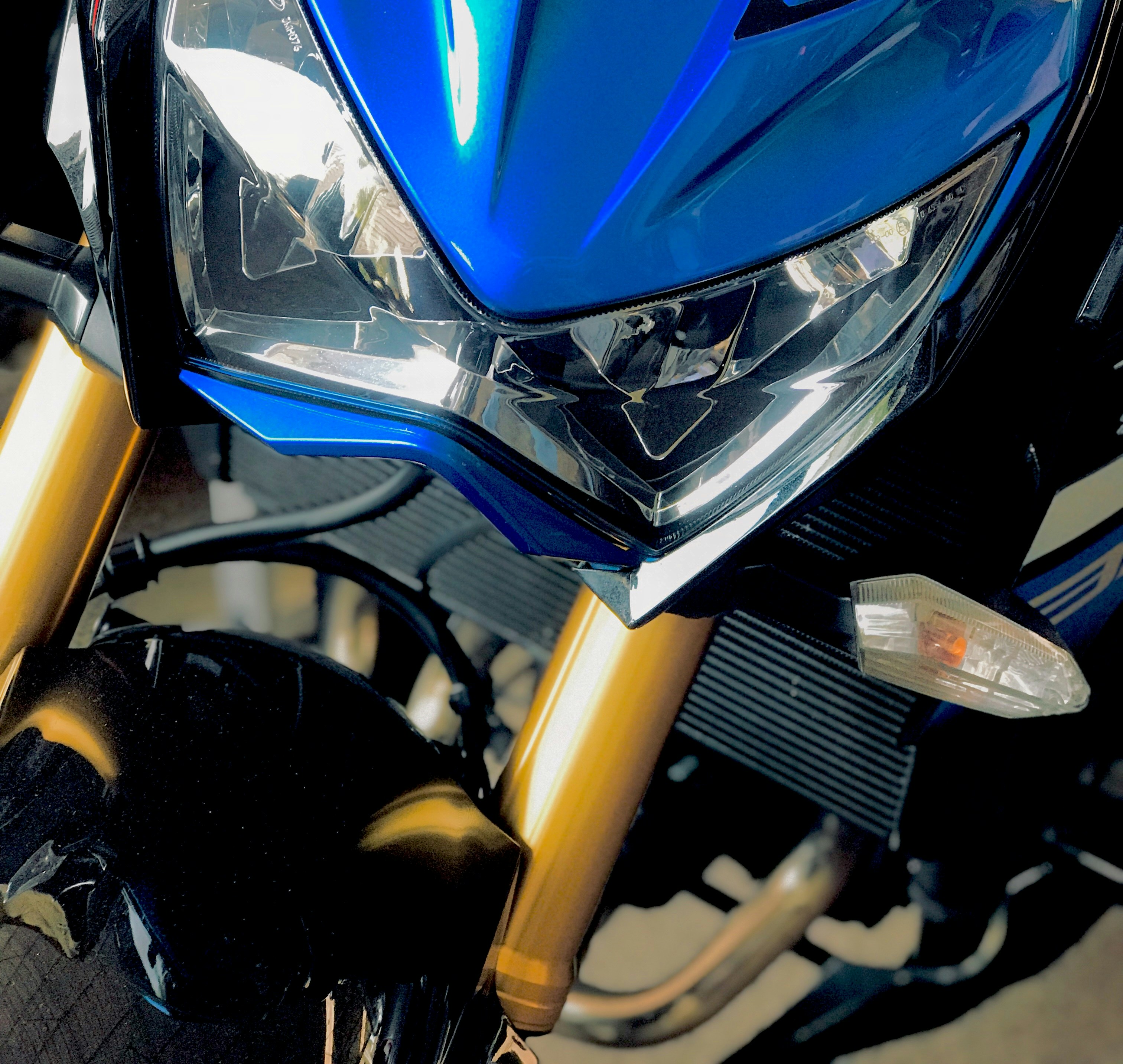 Close-up view of a motorcycle's headlight and front fork, showcasing sleek design and metallic finishes.