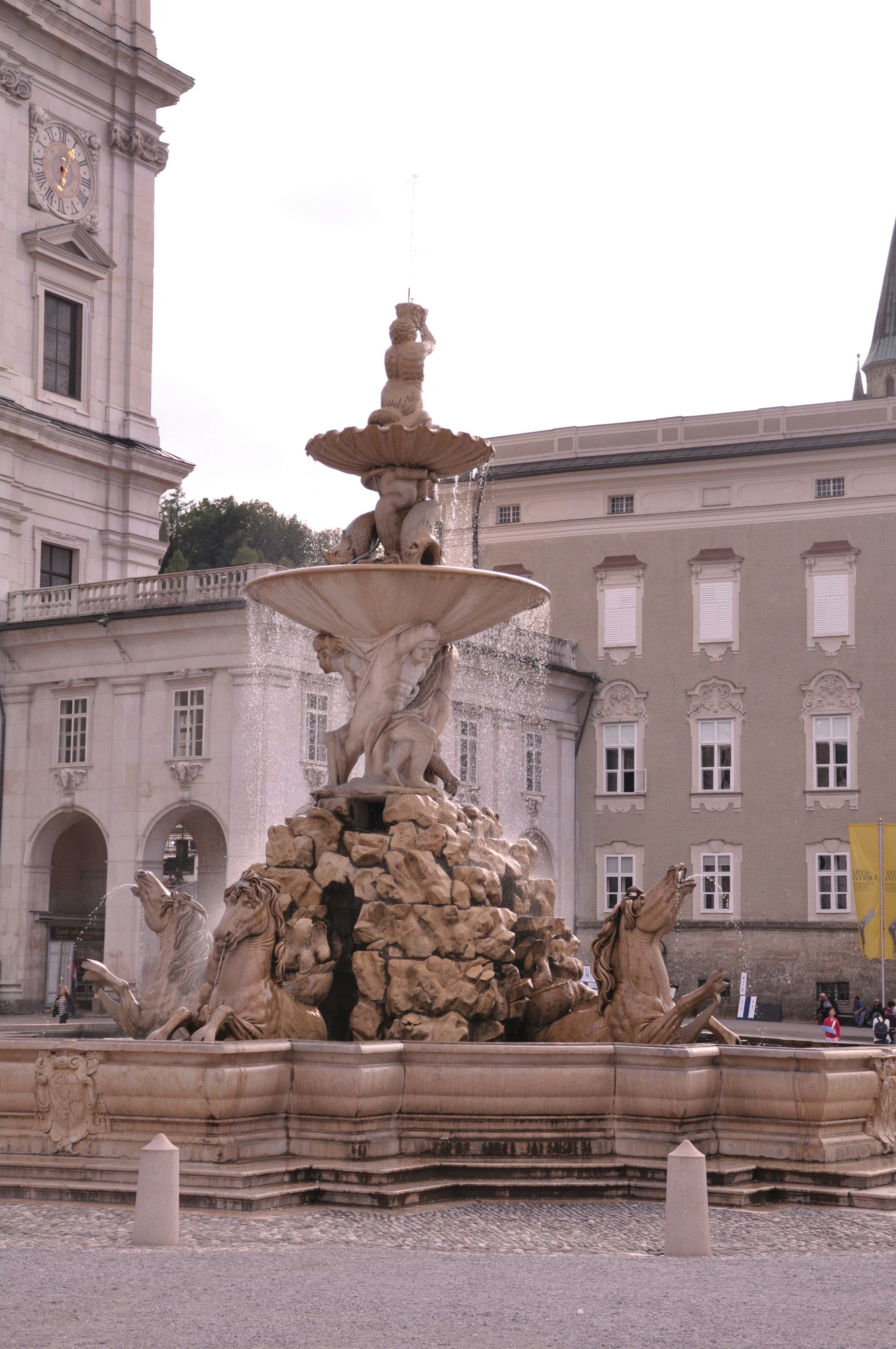 Majestic fountain featuring intricate sculptures of mythological figures surrounded by flowing water, set against a historic backdrop.