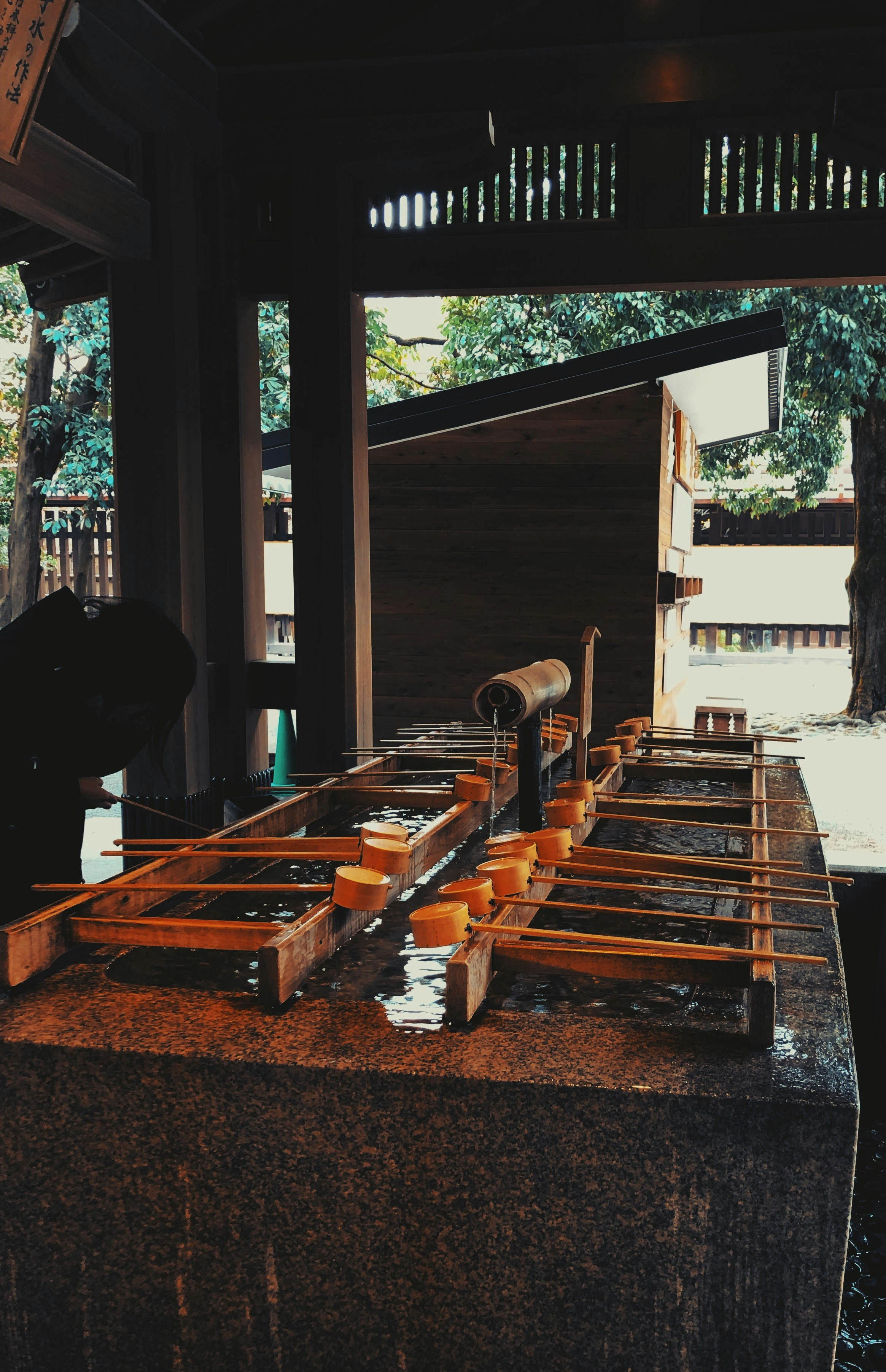 Traditional Japanese water basin for purification, featuring wooden ladles and a tranquil setting. The scene evokes a sense of calm and cultural significance.