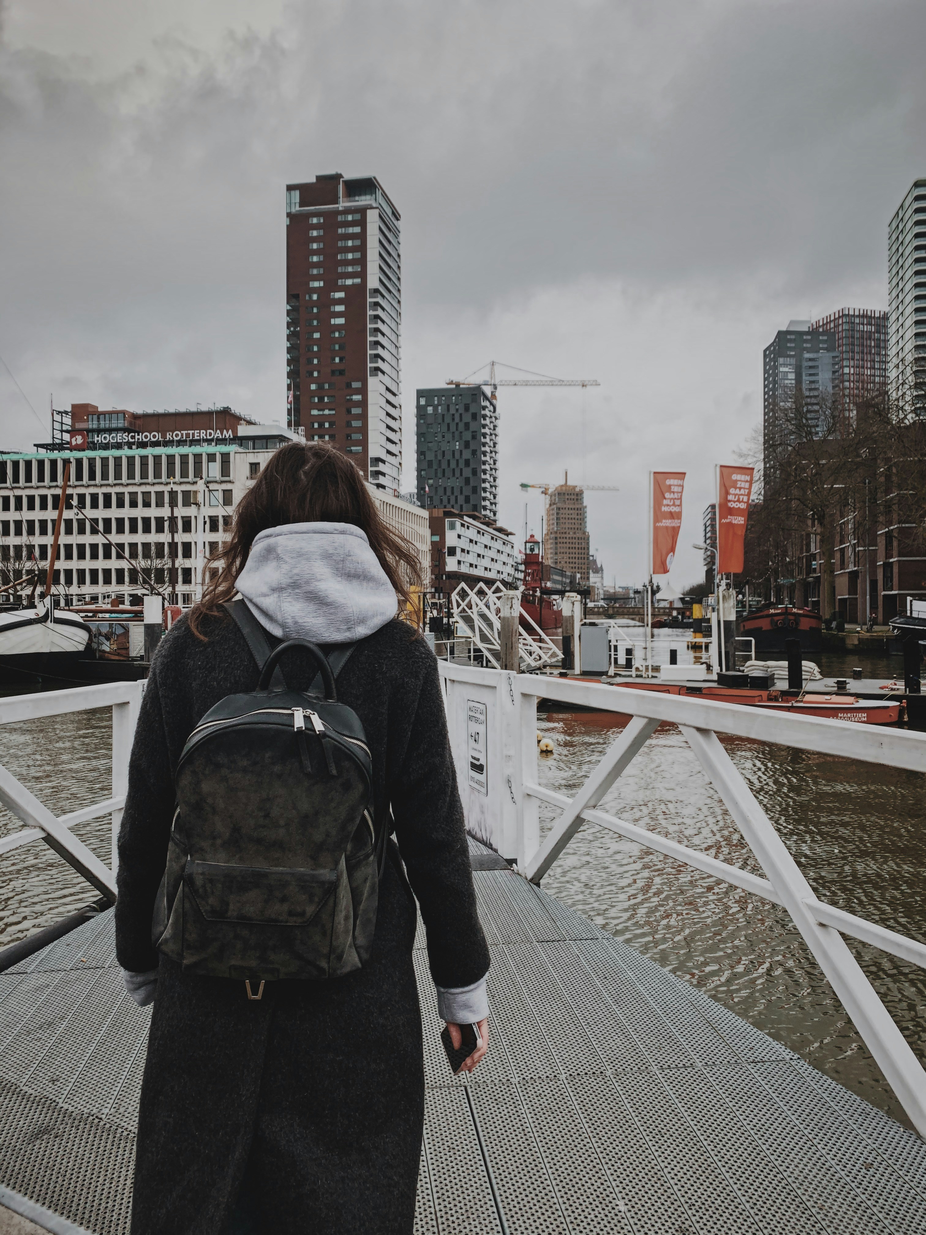 Backpacker on a Rotterdam canal bridge beneath a moody, cloud-laden sky