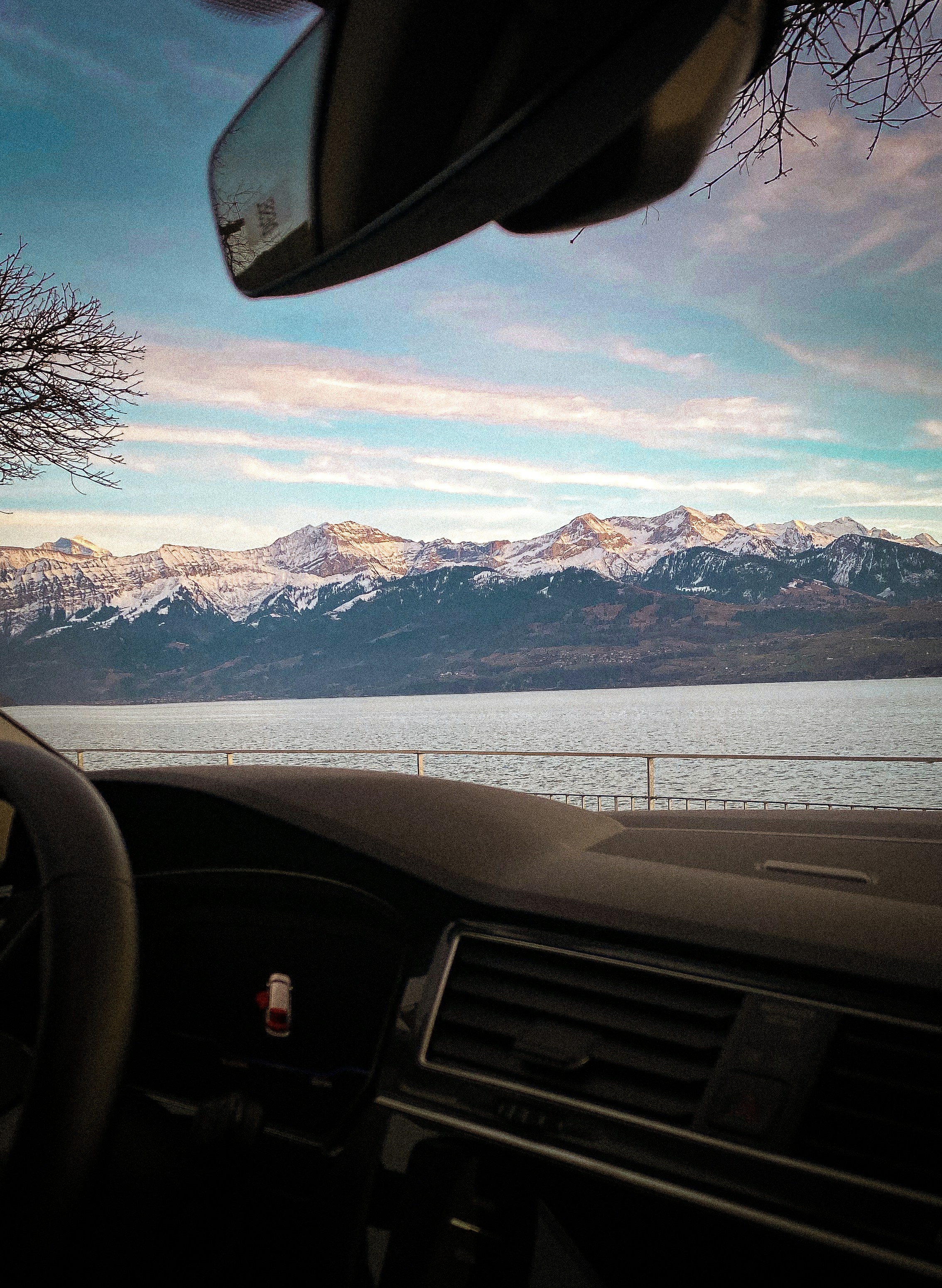 Snow-Dusted Ridge Framed by a Car Window Over a Serene Lake