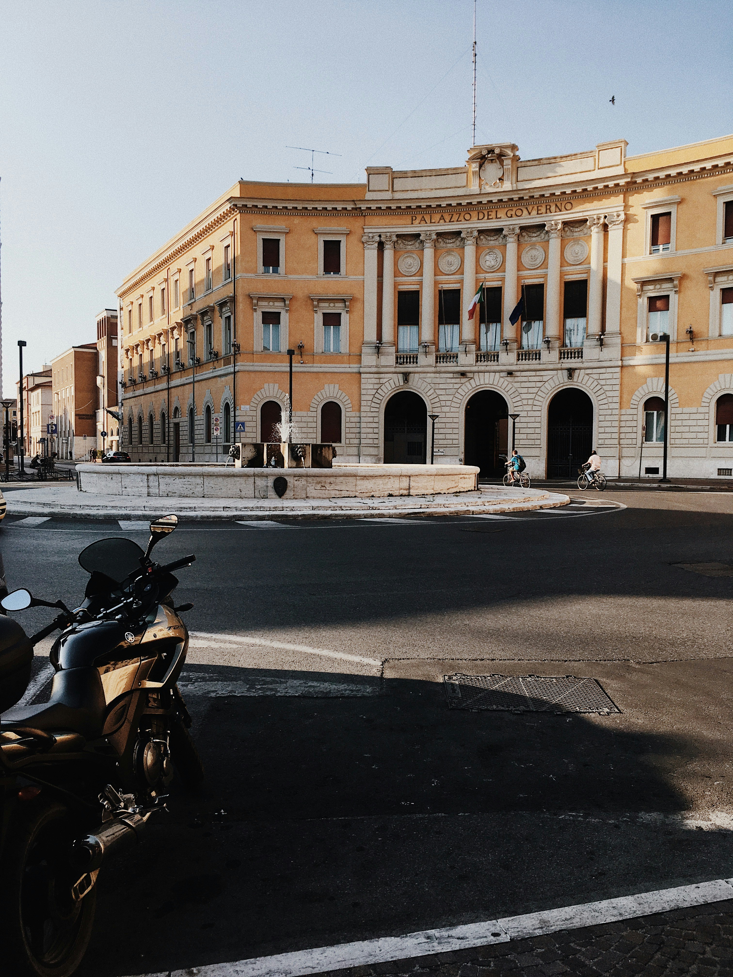 Sunlit Palazzo del Governo: Arched Facades, Fountain, and a Quiet Roundabout