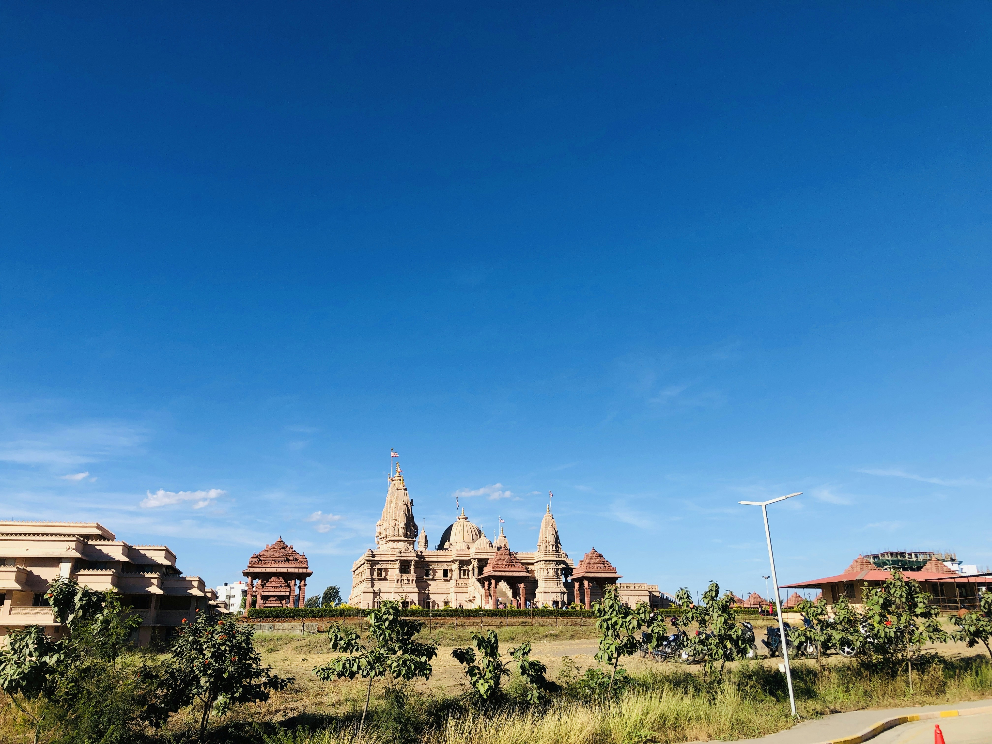 Brown and white concrete temple complex with intricate details under a vibrant blue sky.