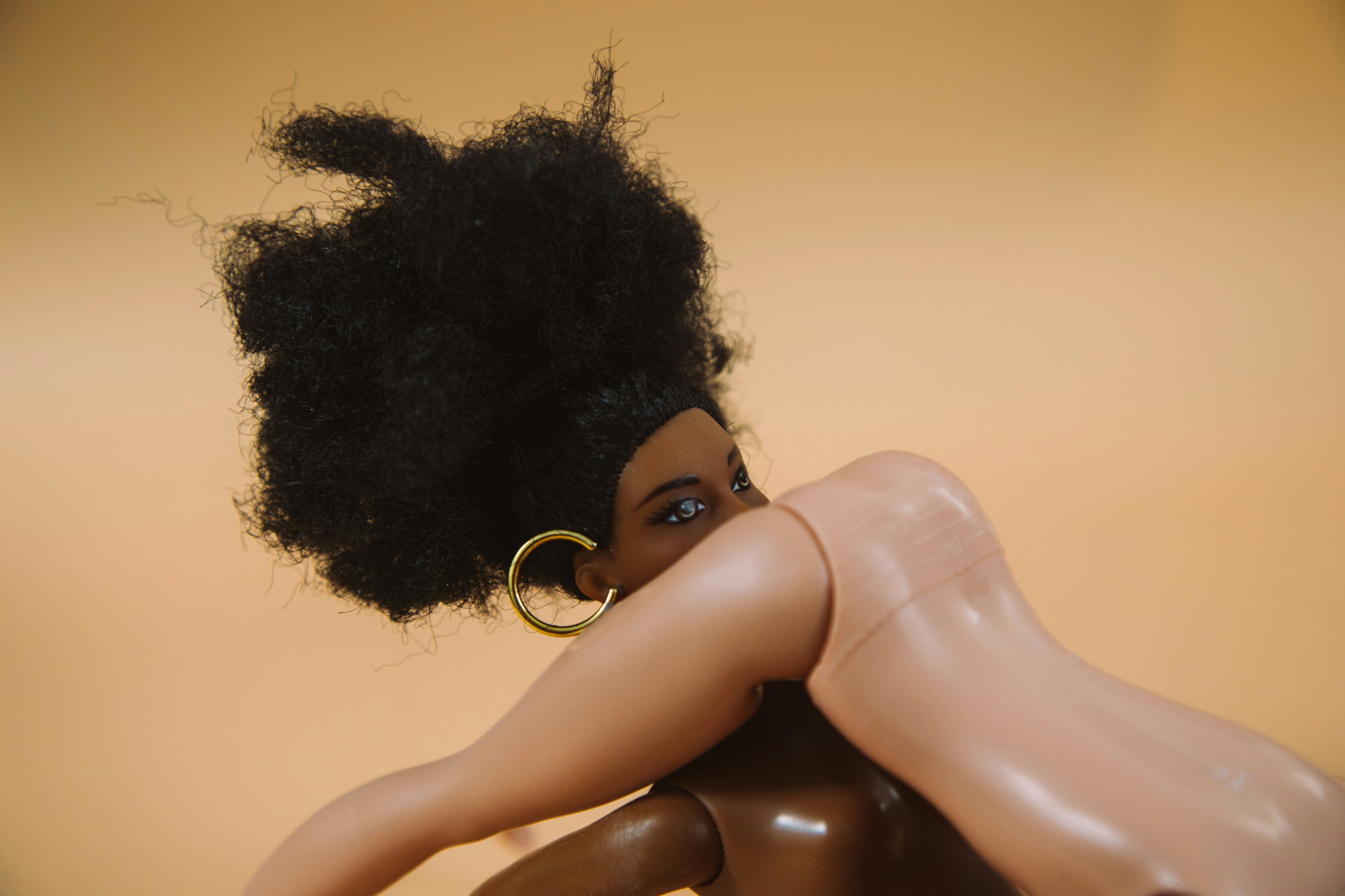 Close-up of a poised figure: Afro puff and gold hoop in warm light