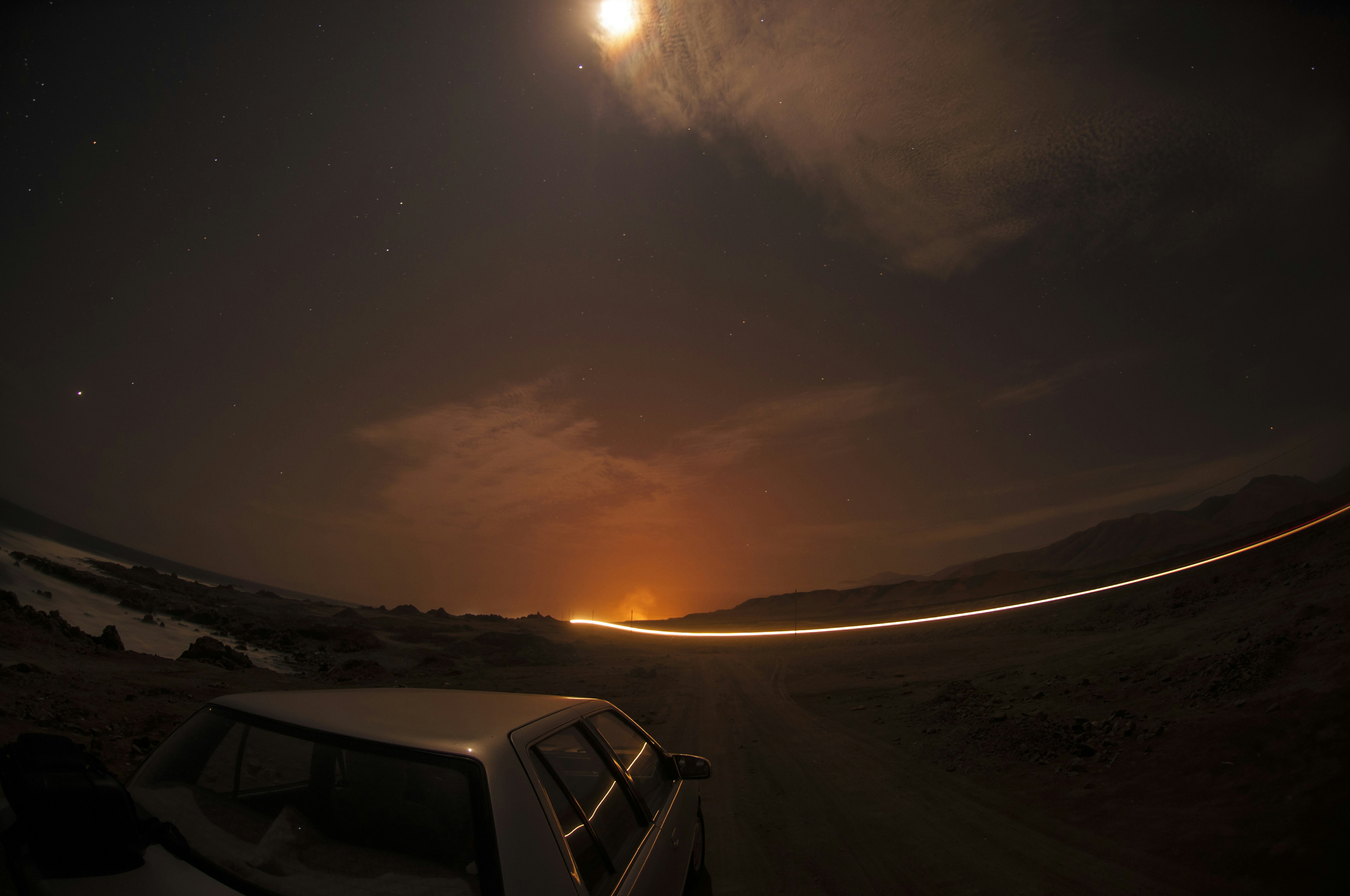 Ember Horizon Drive: Long-Exposure Night Scene with Star Trails and Car Silhouette