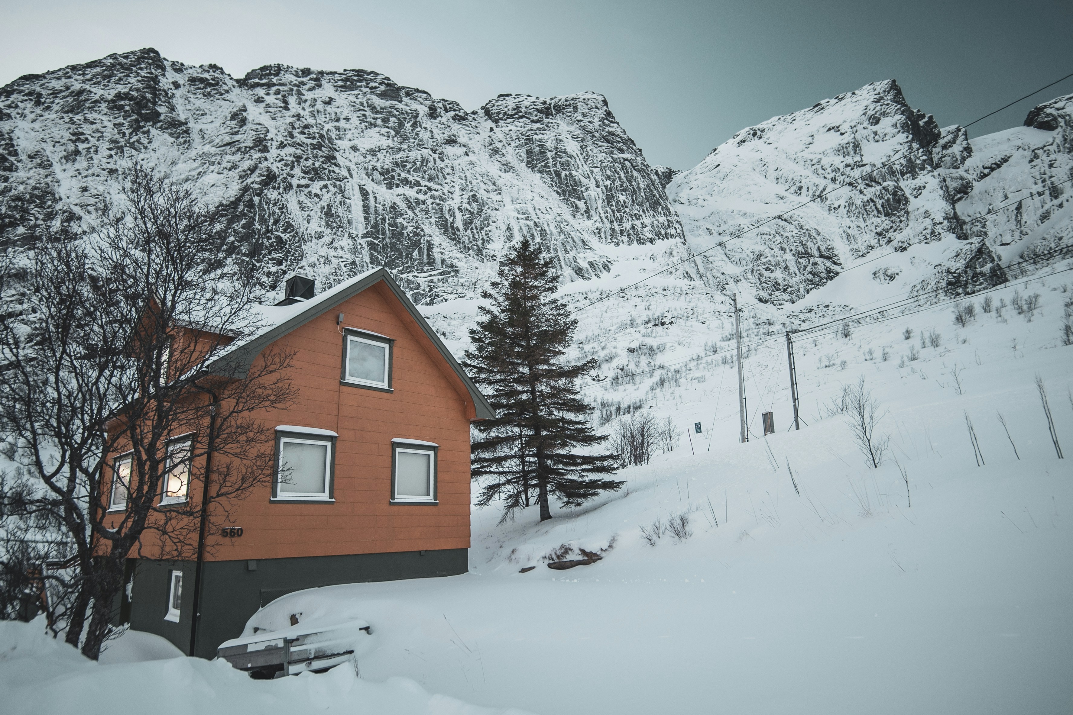 Orange house nestled in a snowy mountain landscape under a soft, overcast sky.