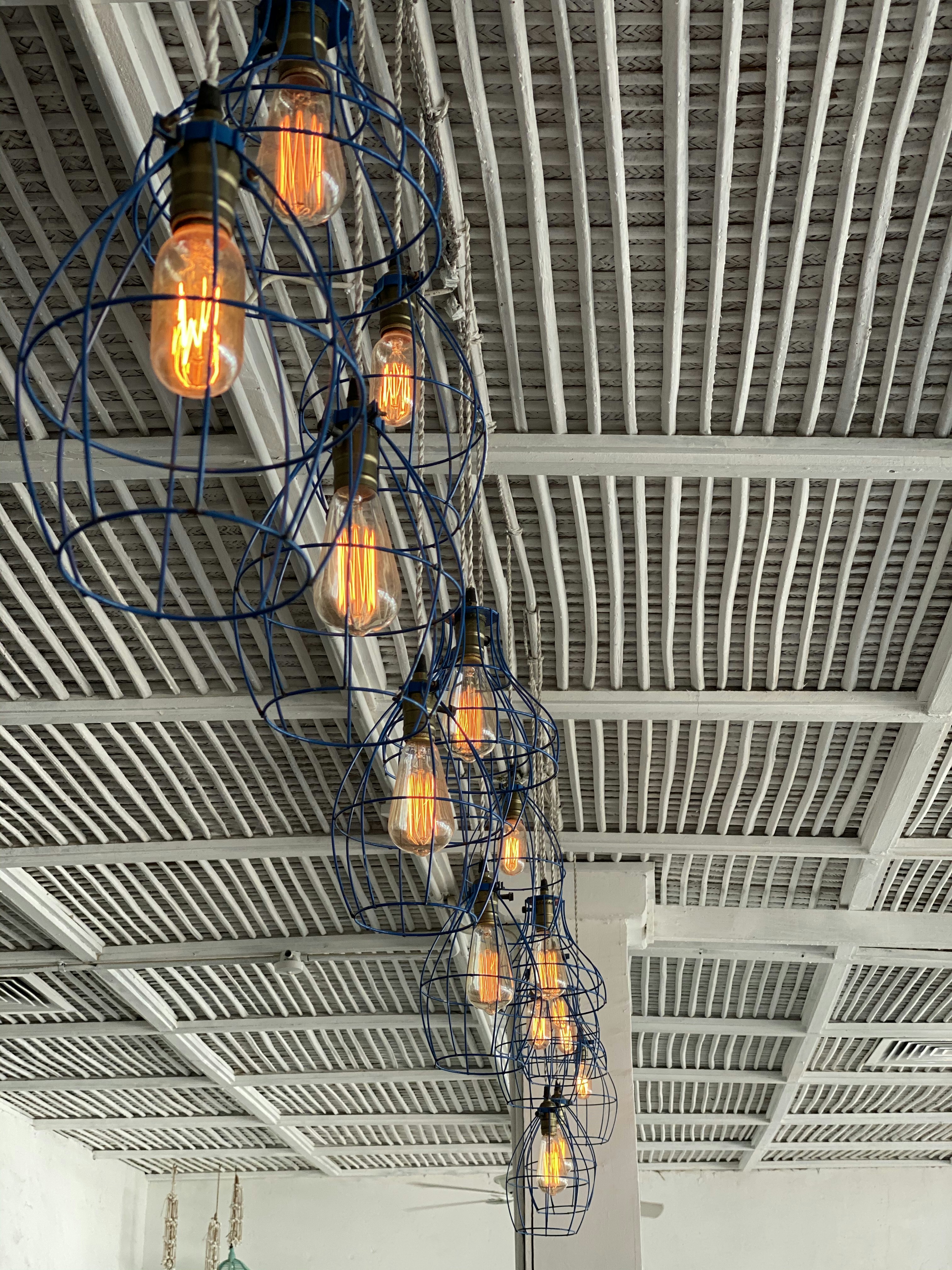 Blue Cage Edison Orbs Drifting Along an Industrial Ceiling