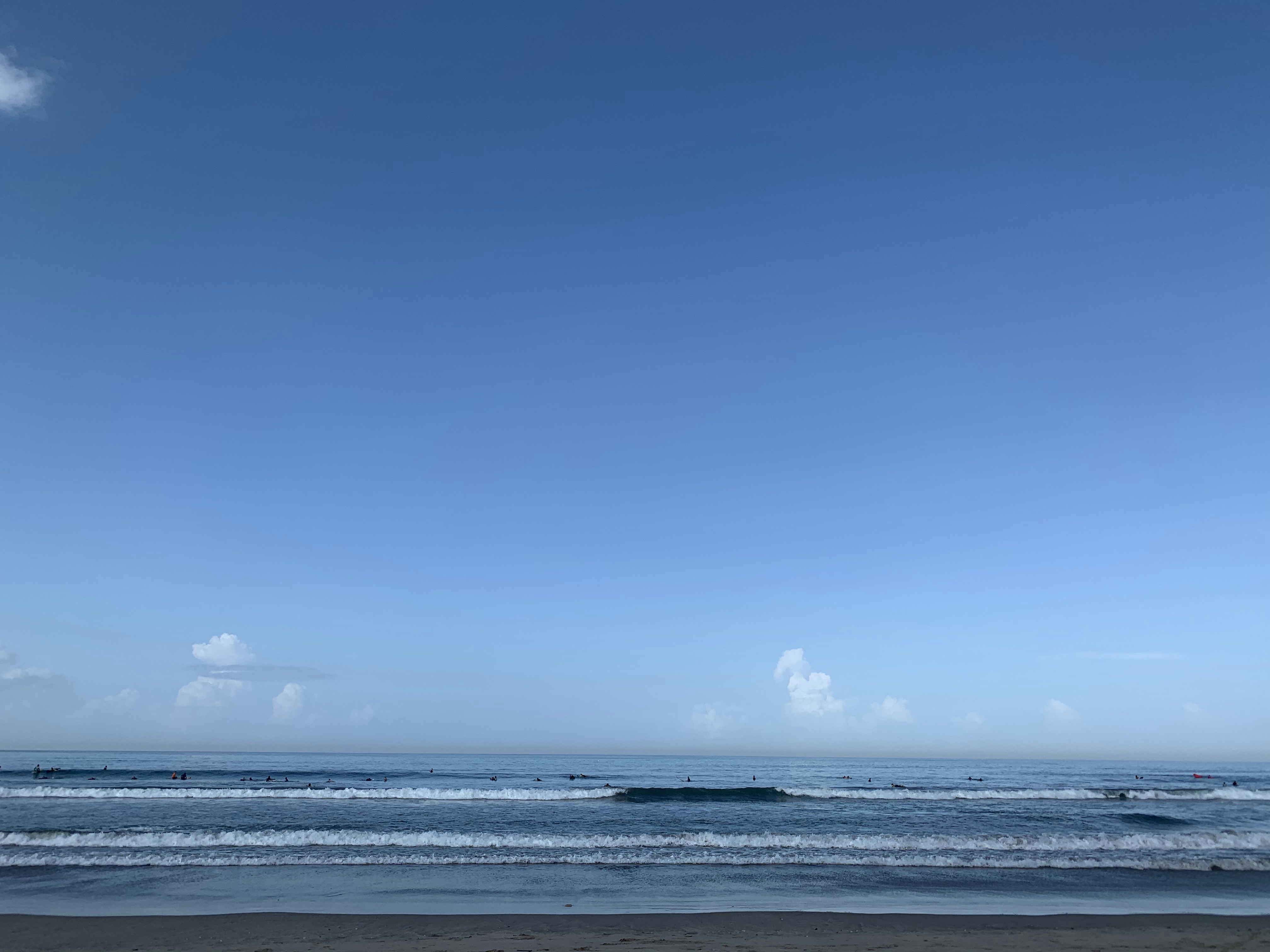Gentle waves lapping at the shore under a clear blue sky, evoking a sense of tranquility and openness.
