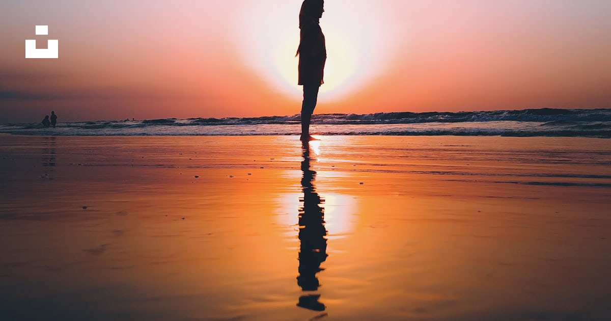 Silueta De La Persona De Pie En La Playa Durante La Puesta Del Sol Foto