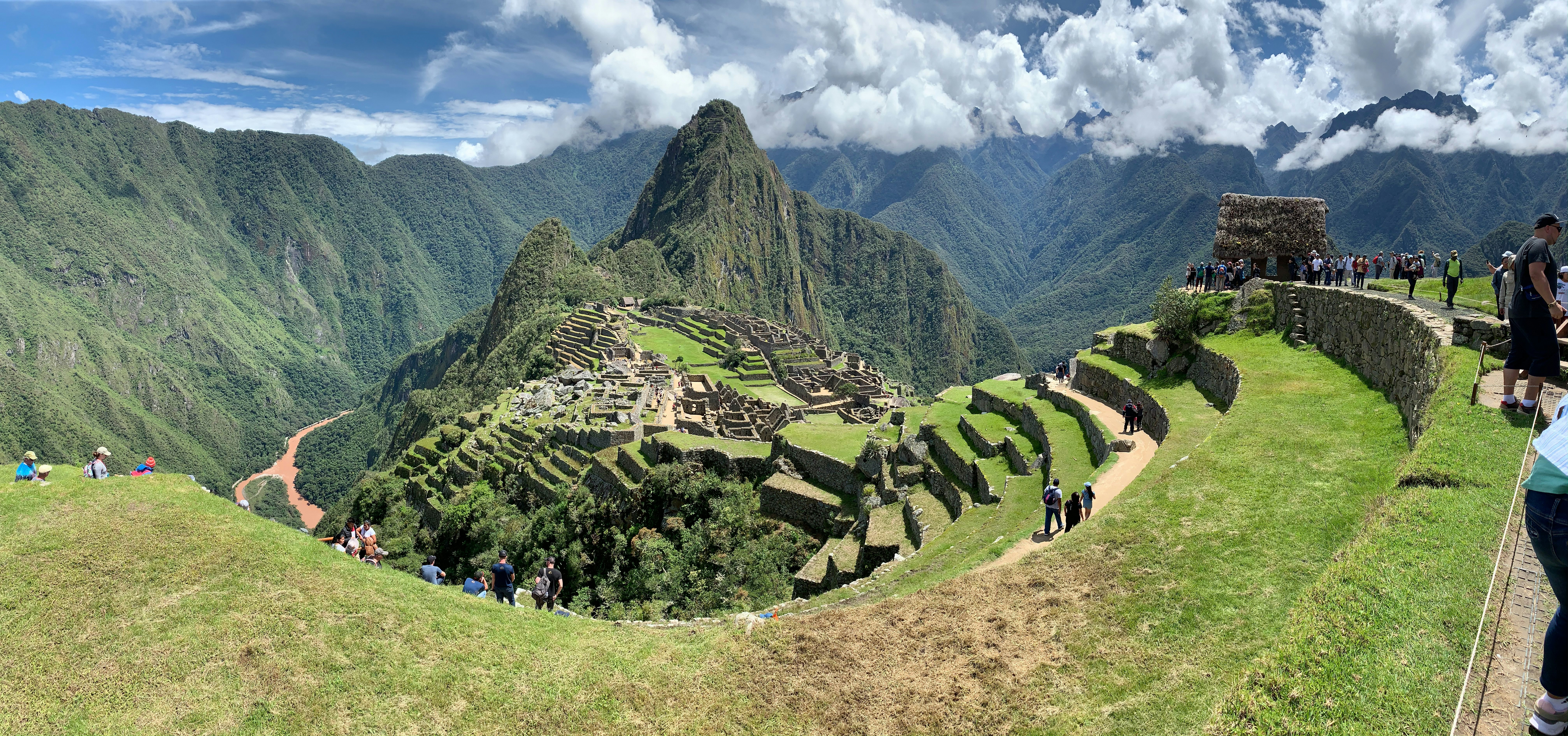 Panoramic view of Machu Picchu with dramatic mountain backdrop under a cloudy sky.