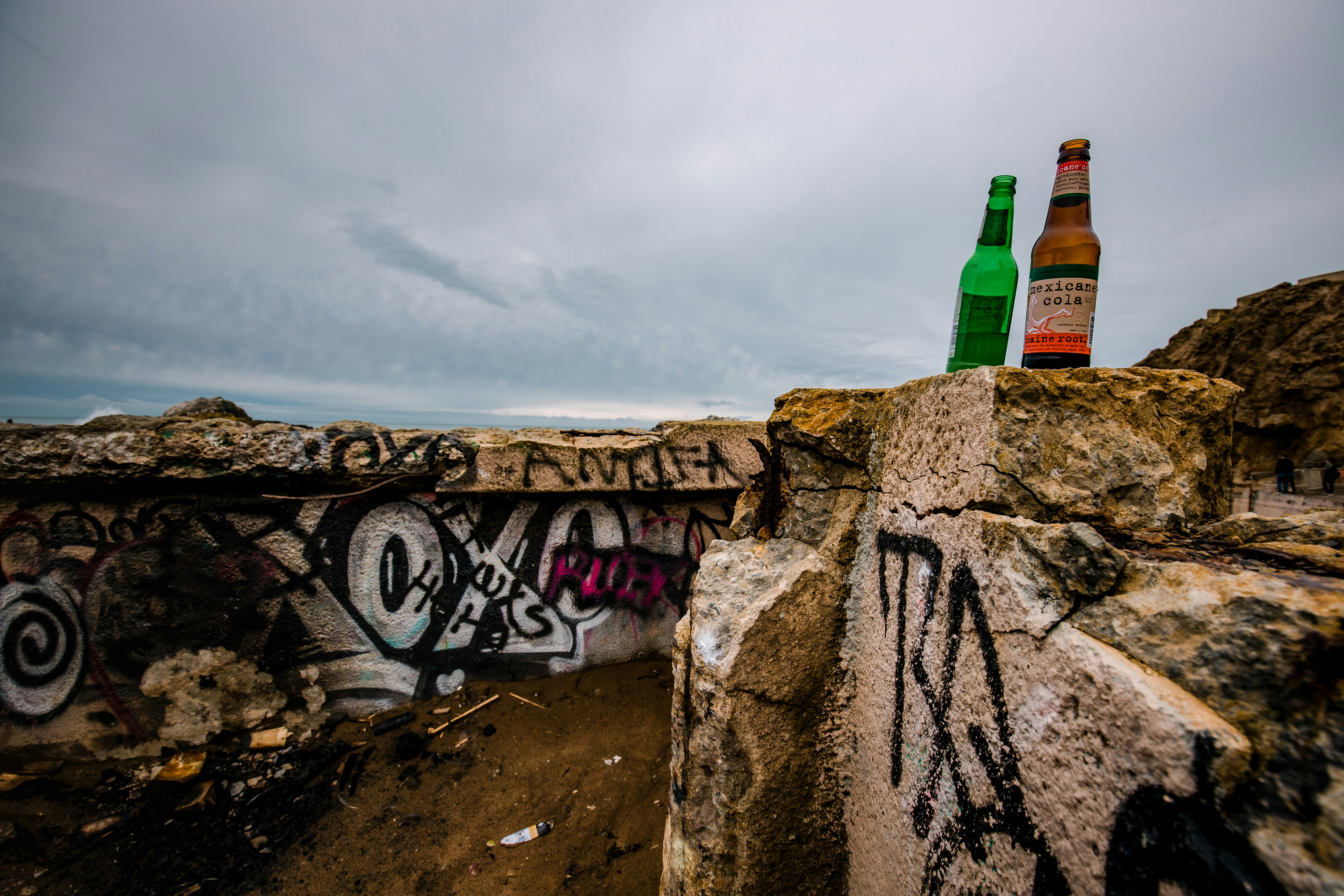 Two Bottles on the Graffiti Wall: A Seaside Concrete Edge
