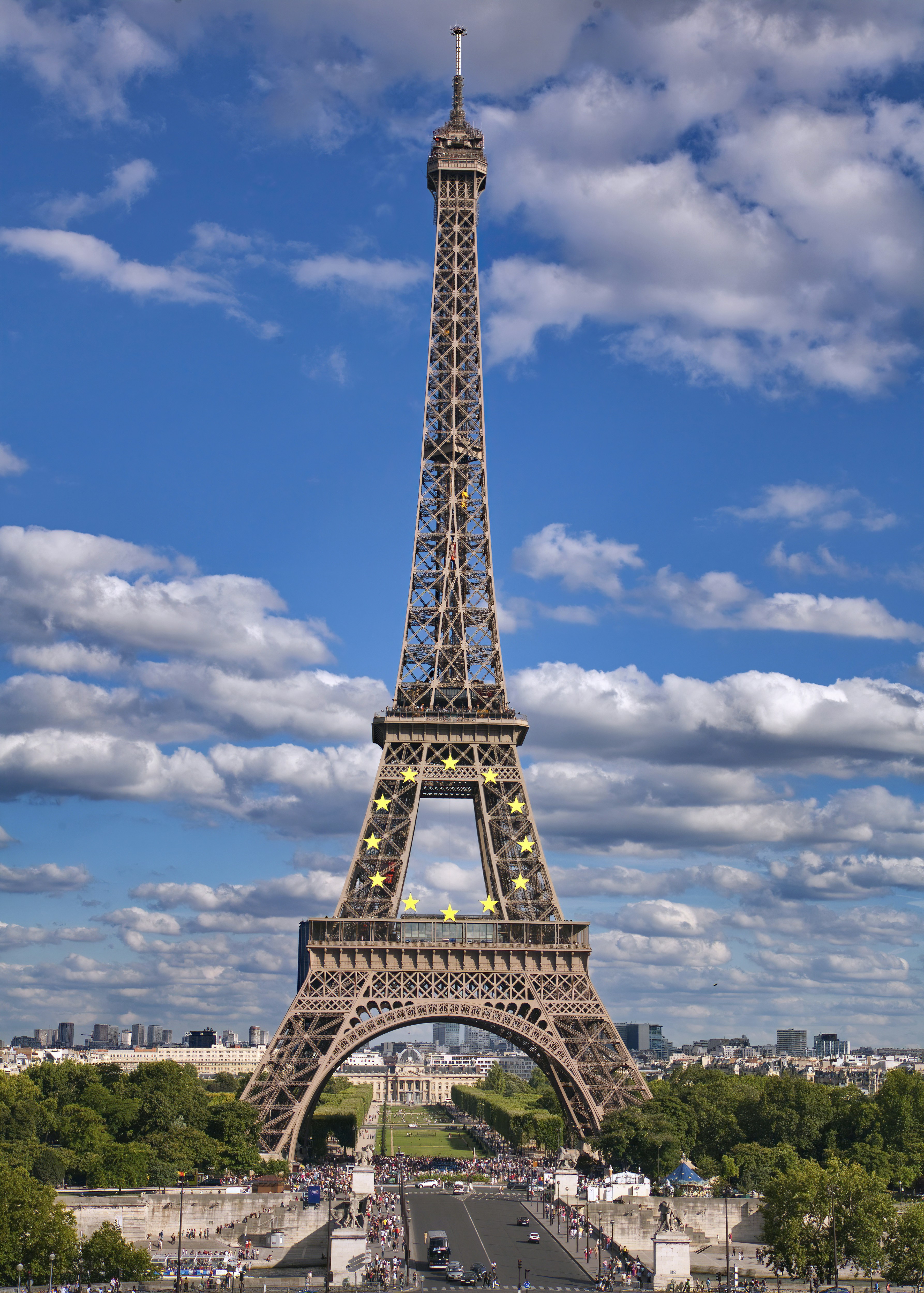 Eiffel Tower adorned with stars under a vibrant sky, showcasing its grandeur against a backdrop of fluffy clouds. The scene captures the iconic structure's architectural beauty and its significance in the Parisian landscape.