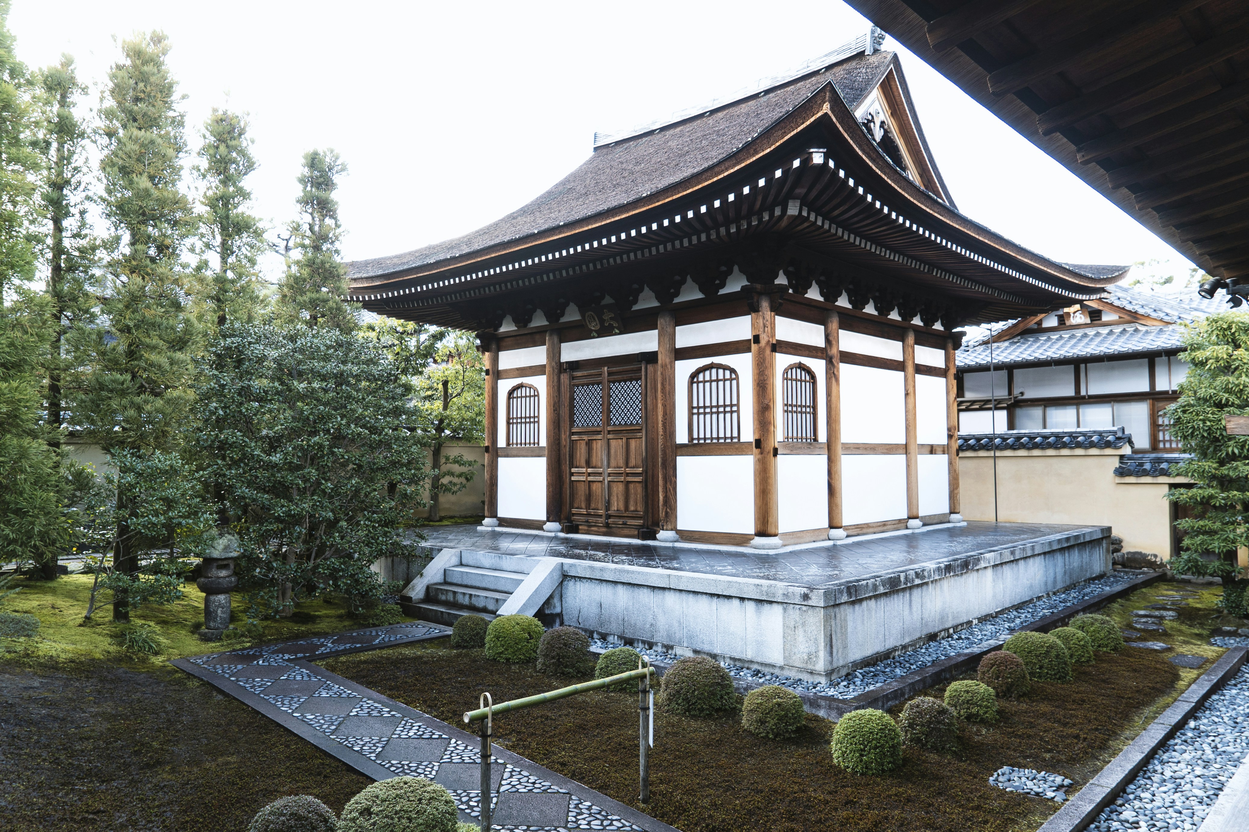 Traditional Japanese temple surrounded by meticulously landscaped gardens, showcasing wooden architecture and natural elements.