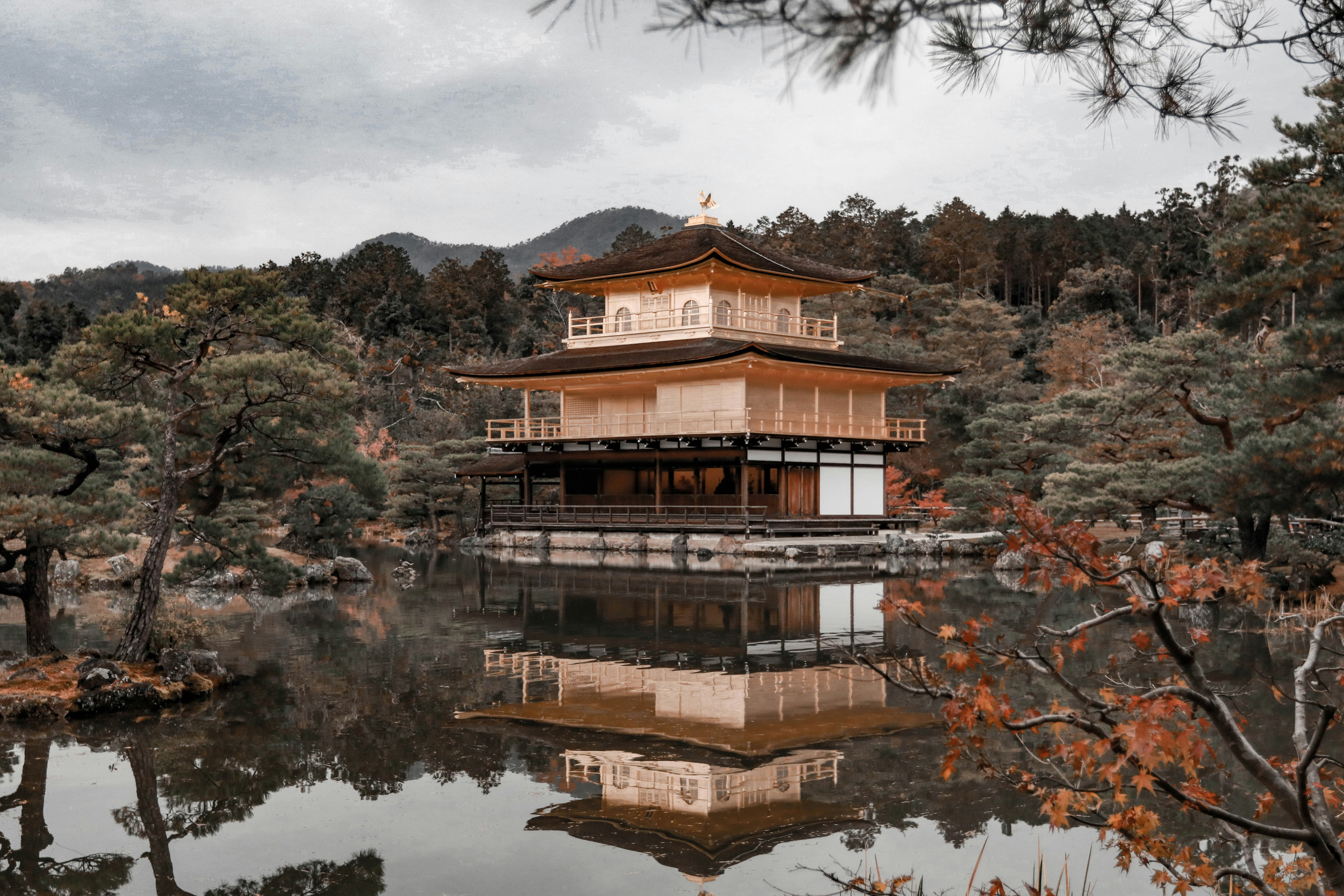 Golden pavilion surrounded by tranquil waters and lush greenery, reflecting its beauty in the still lake below.