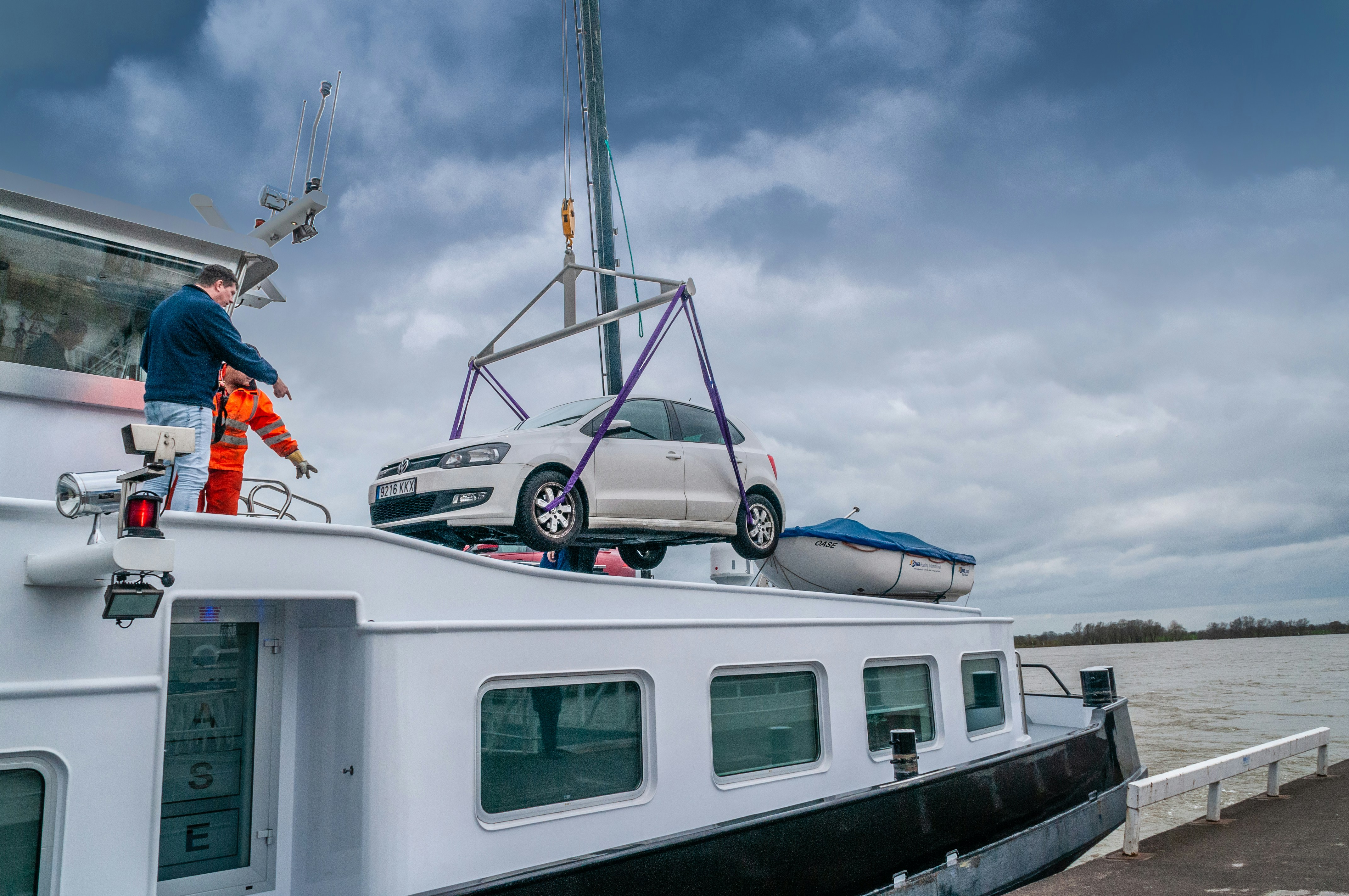 Crane Lift Aboard: White Car Hoisted Onto a River Ferry