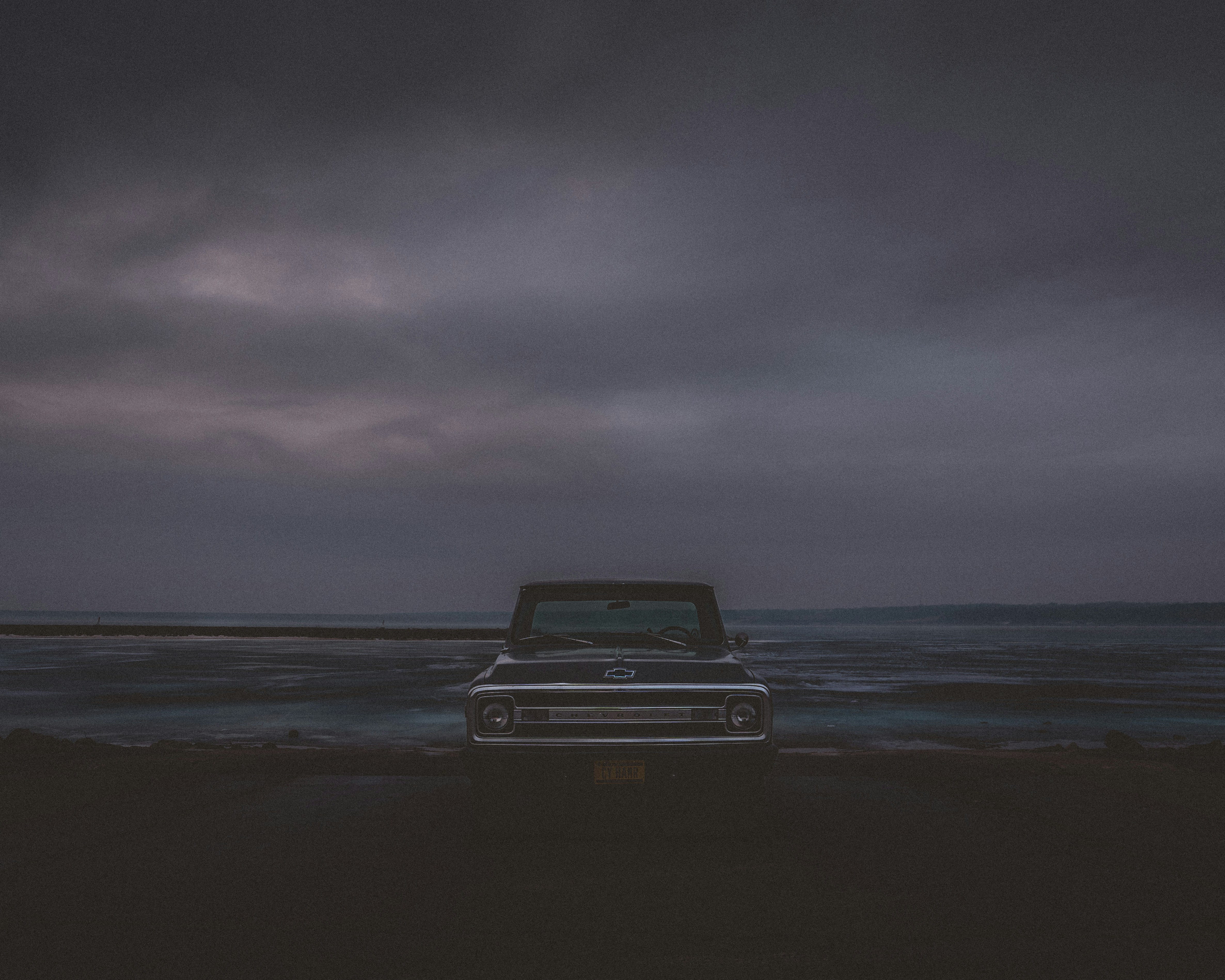Midnight Seaboard: A vintage pickup anchors the dim shoreline beneath a brooding sky