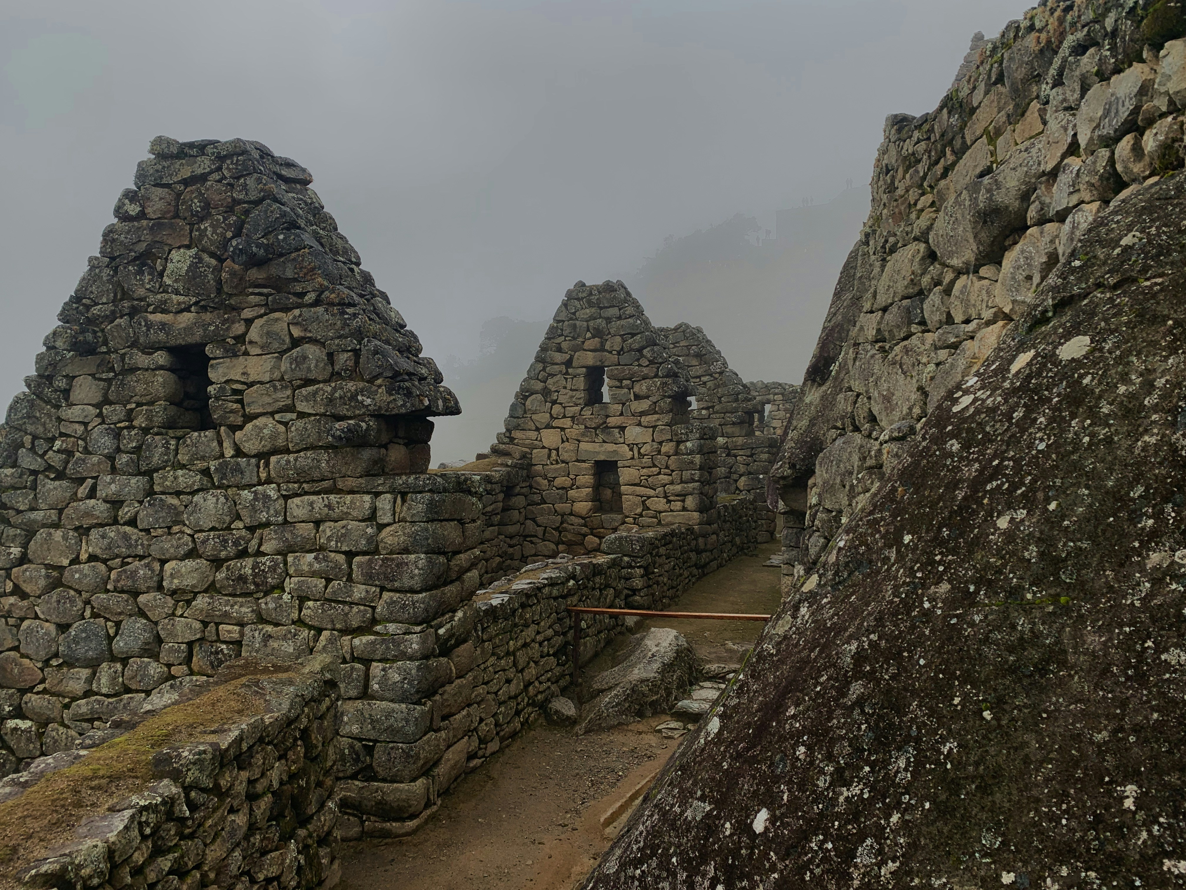Ancient stone structures shrouded in fog at a historic archaeological site.