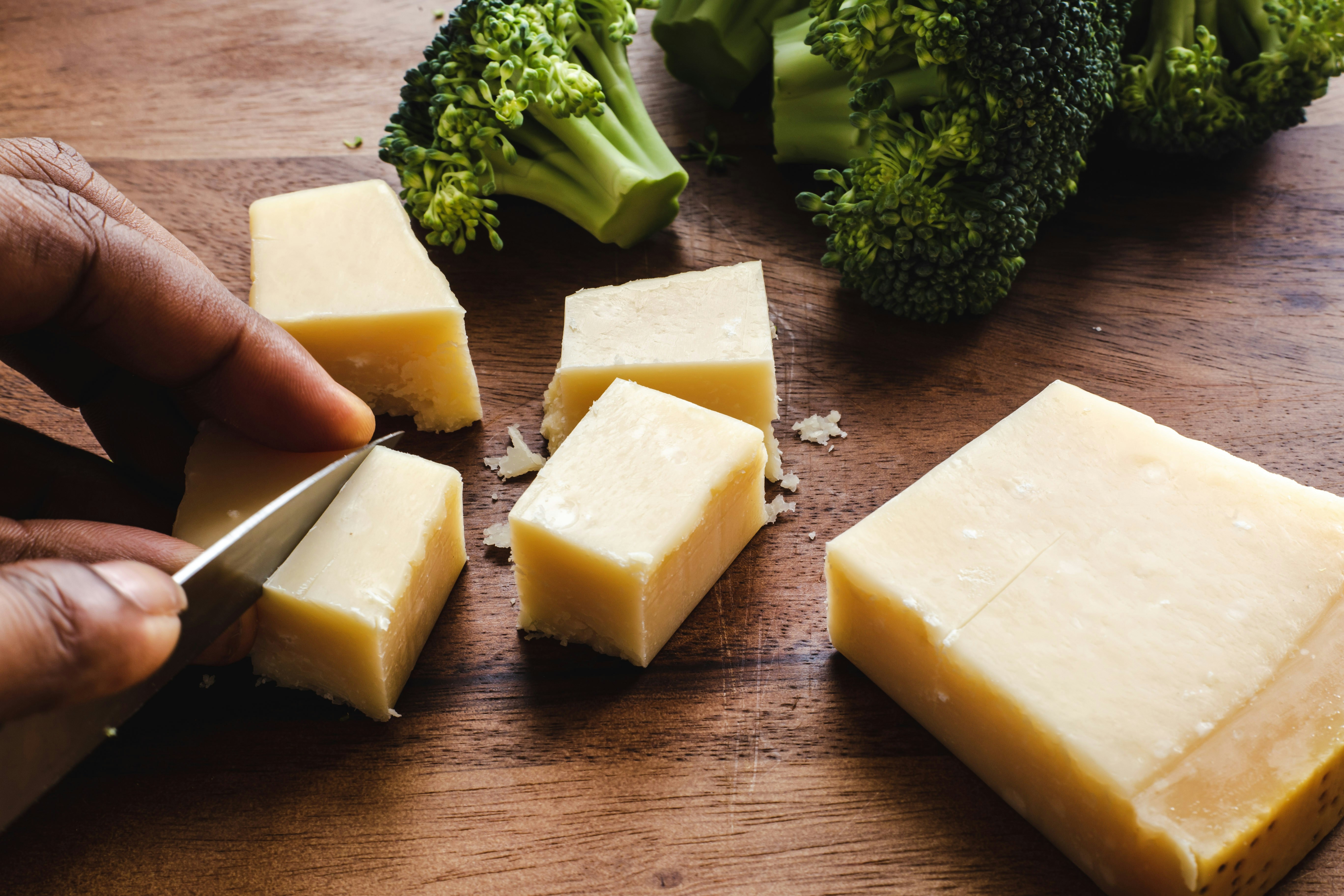 Hand-Sliced Cheese Cubes on a Rustic Cutting Board with Broccoli