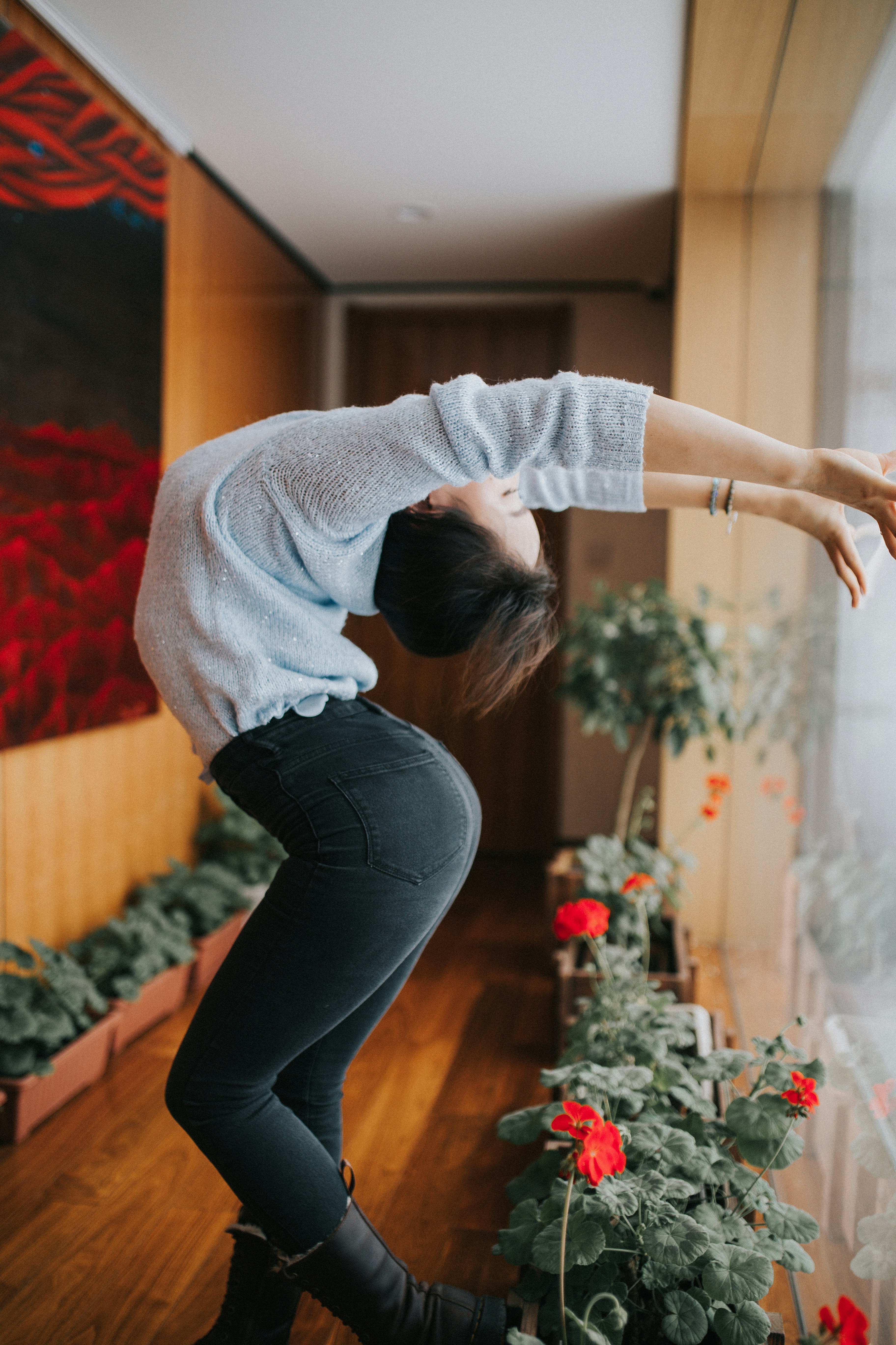 Woman in gray sweater and blue denim jeans bending her body photo ...